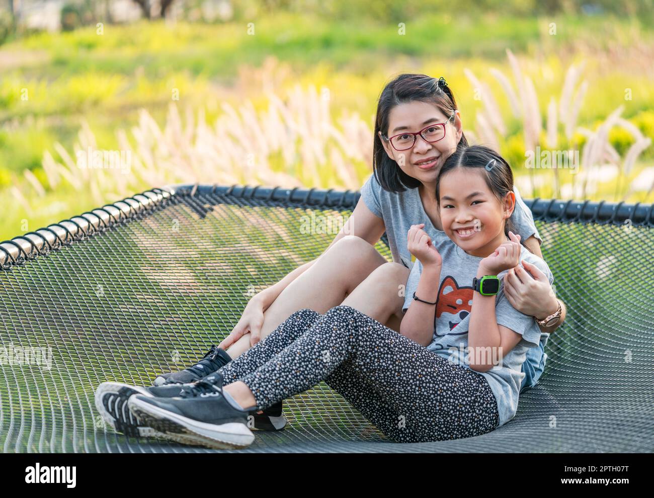 Portrait of Asian single mother and small daughter sitting on big net ...