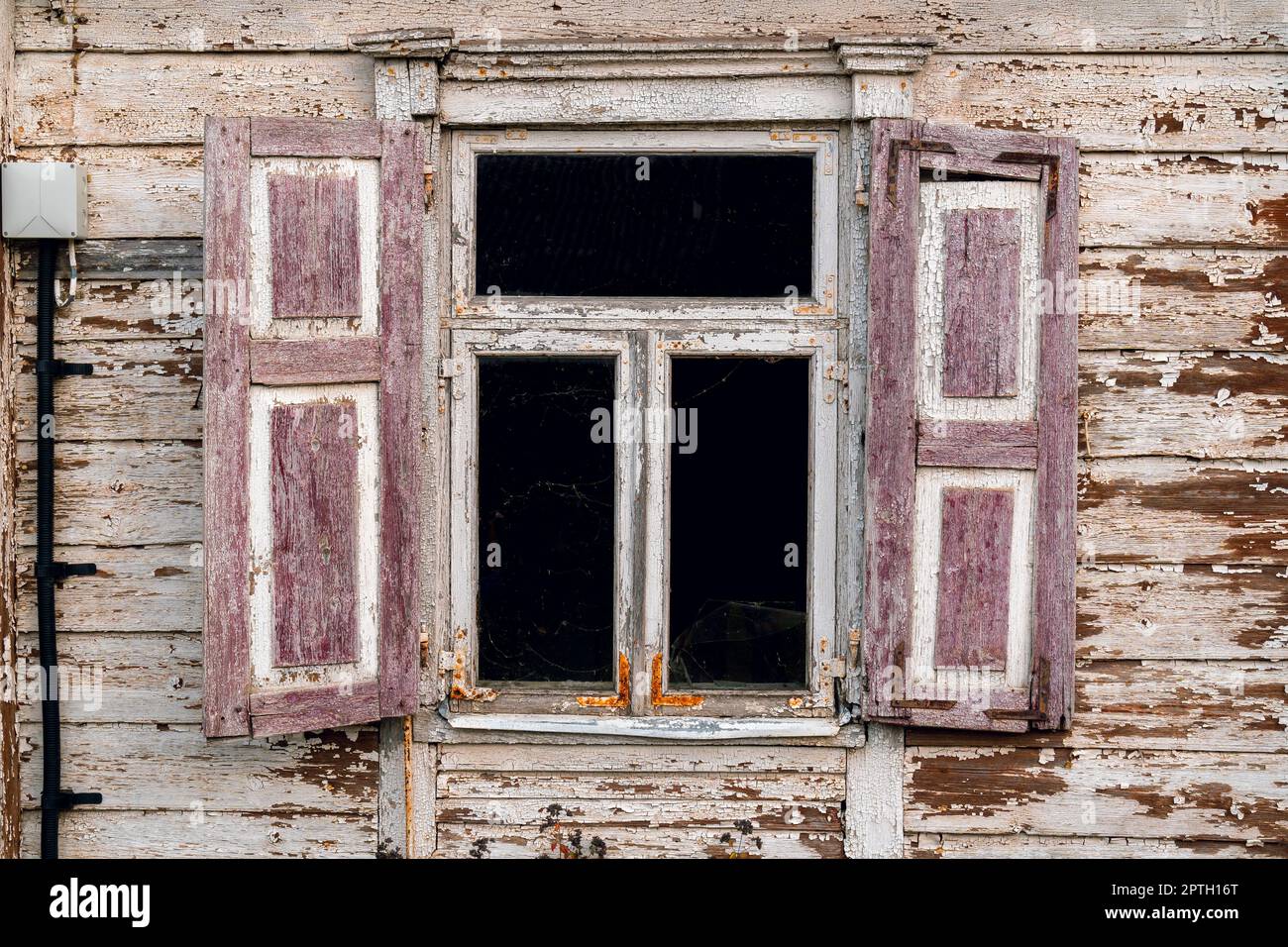 Abandoned wooden house, window with open shutters and broken glass ...