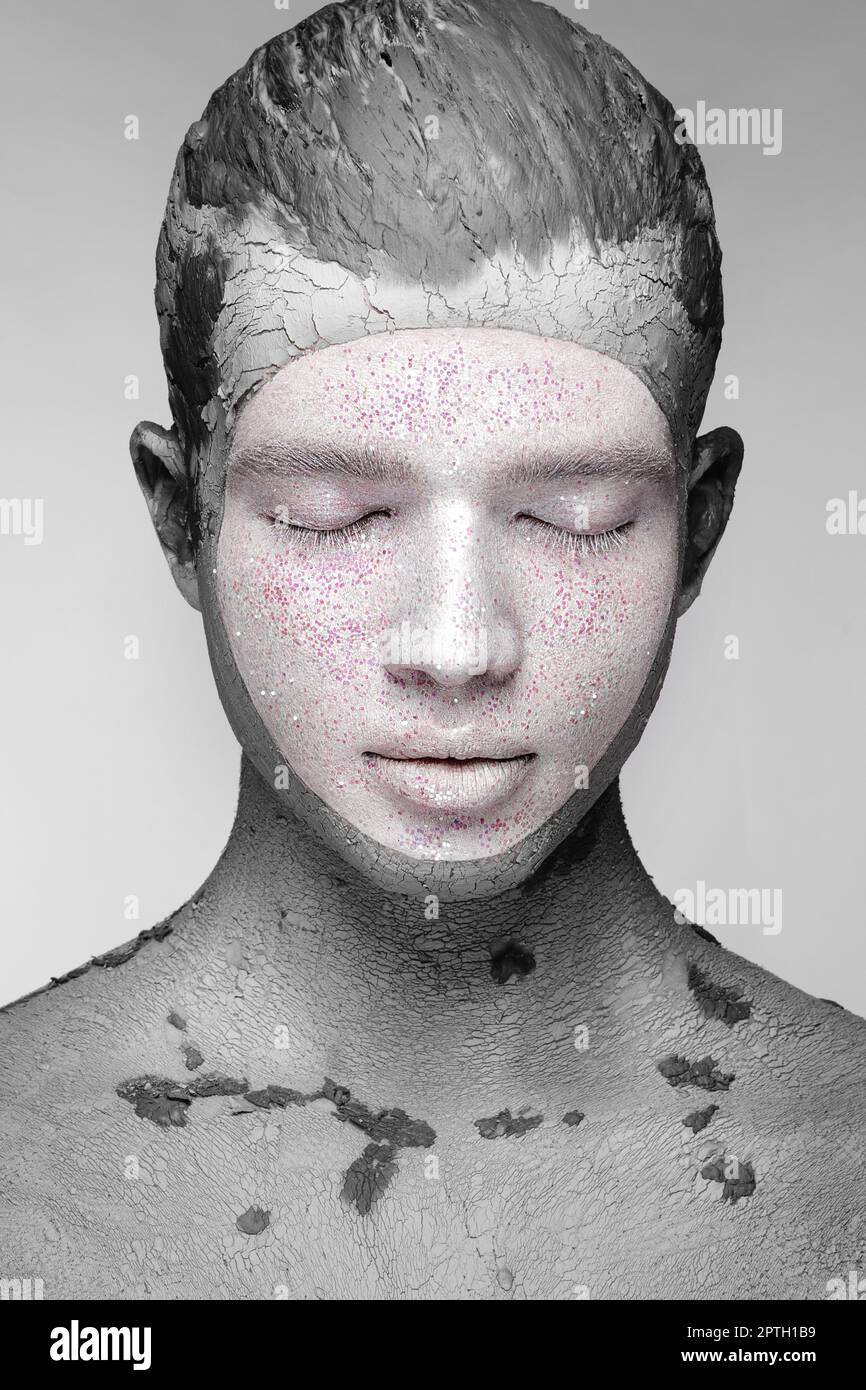 Young man with art creative make-up with mud on his face. Cosmetic mask ...