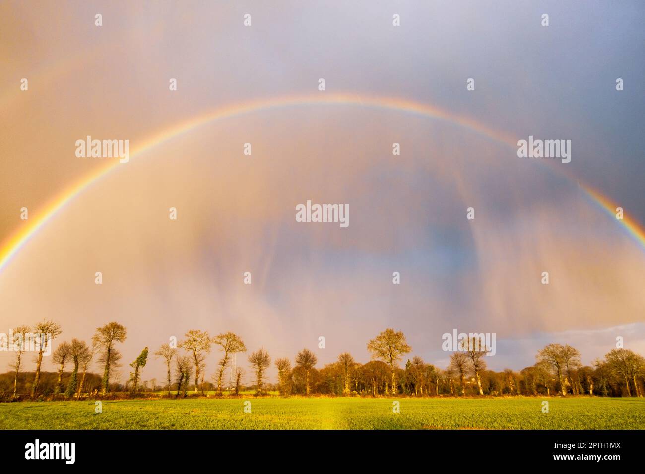 Rural landscape with rainbow over dark stormy sky in a countryside in ...
