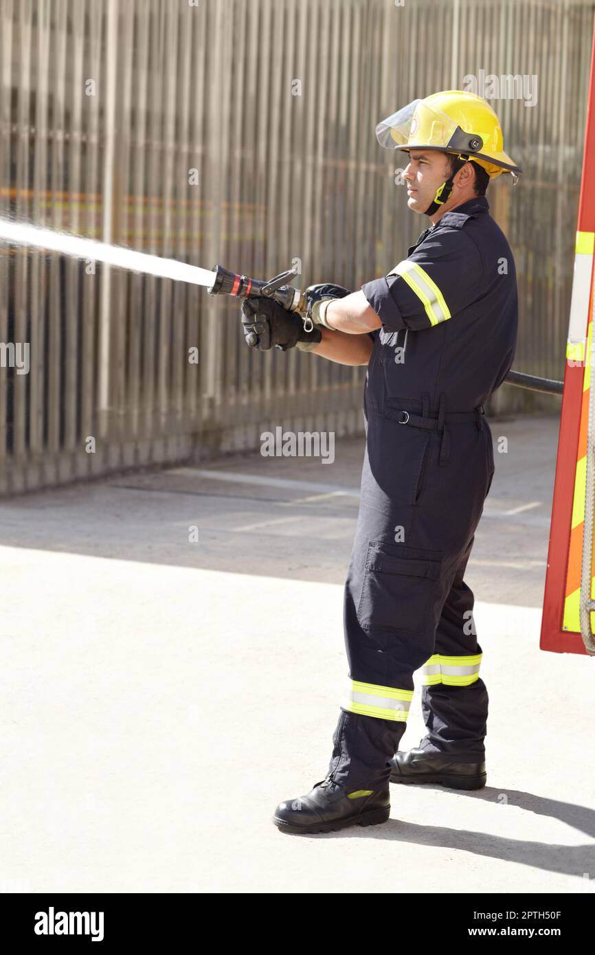 Male firefighter, spray water and emergency worker with helmet, uniform ...