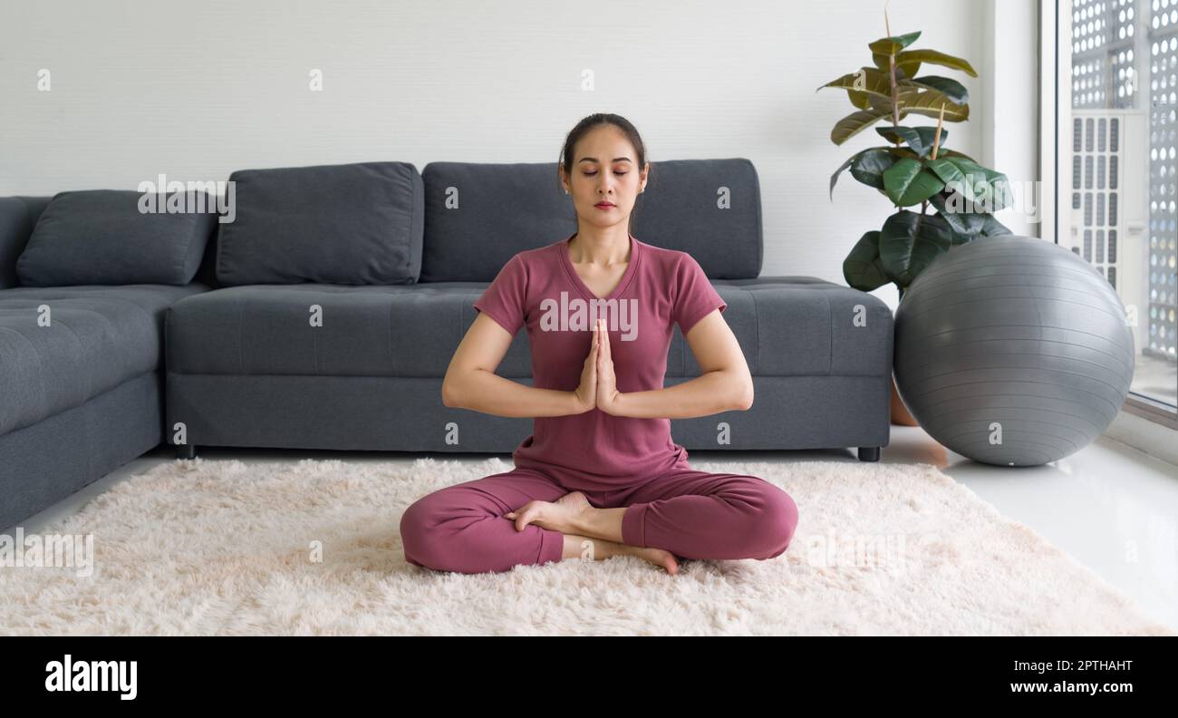 Asian housewife doing Anjali Mudra (Salutation Seal) Yoga Pose during ...