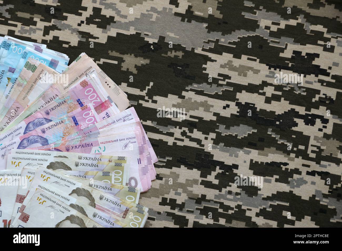 Ukrainian hryvnya bills on fabric with texture of Ukrainian military ...