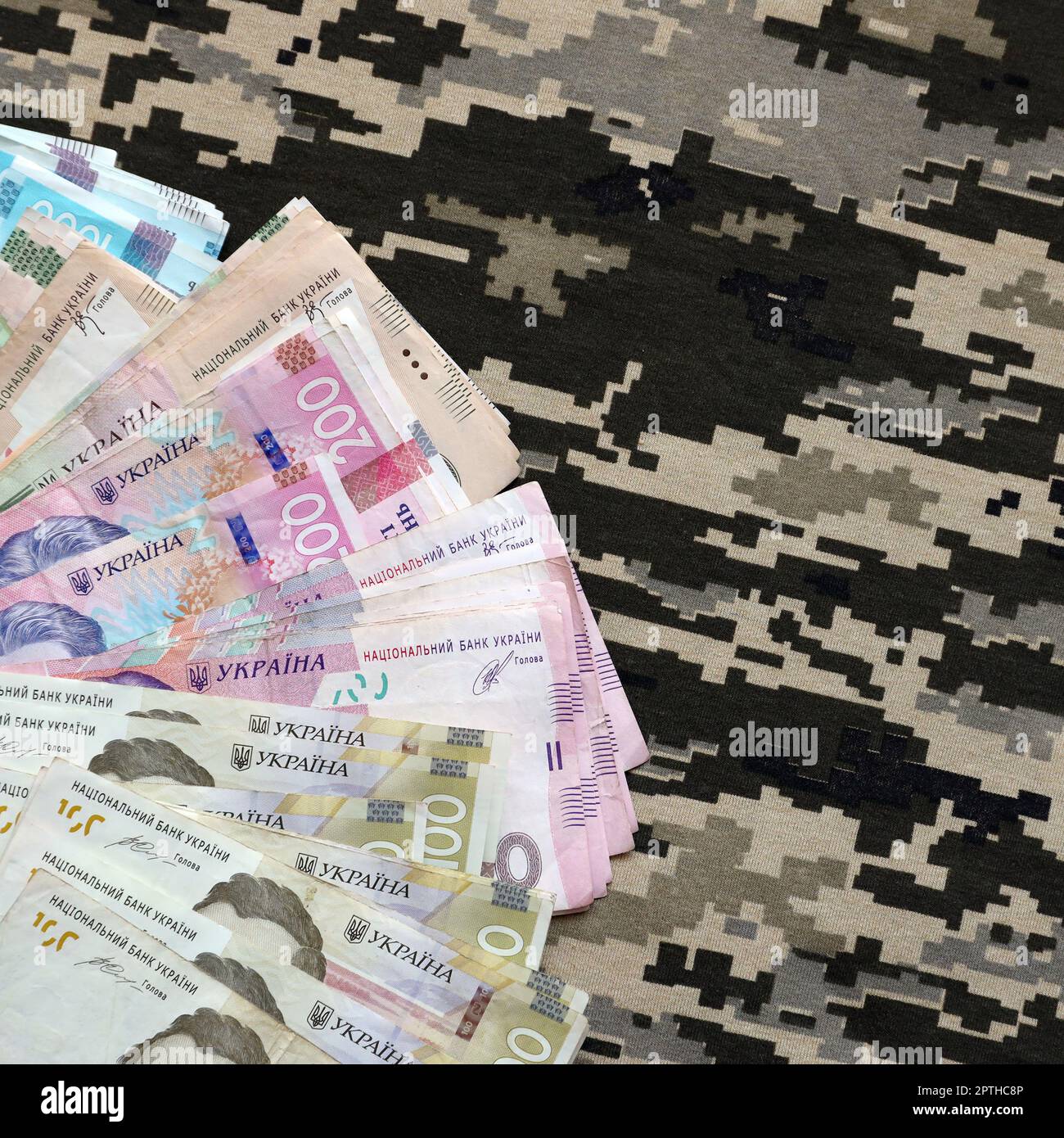 Ukrainian hryvnya bills on fabric with texture of Ukrainian military ...