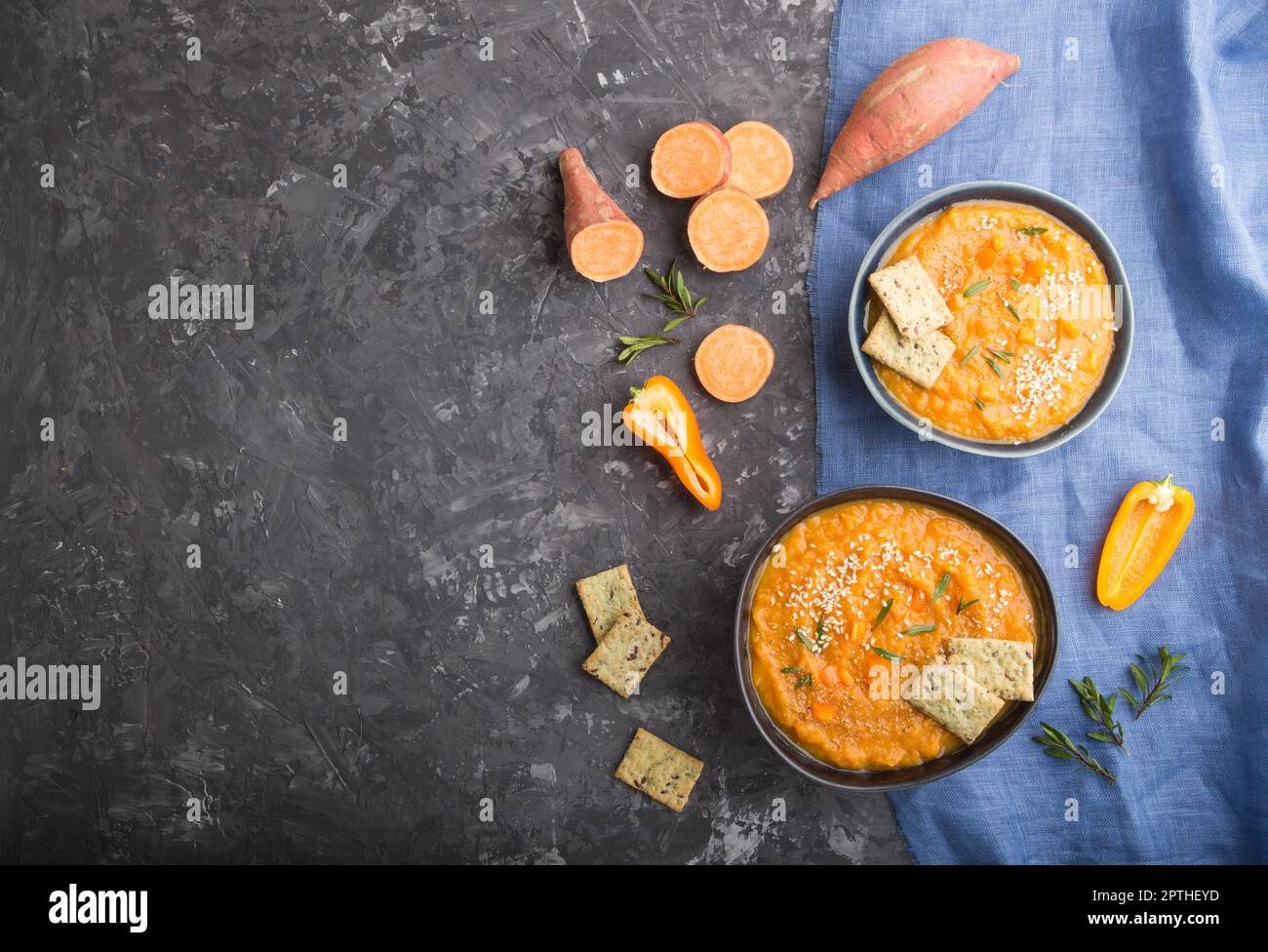 Sweet potato or batata cream soup with sesame seeds and snacks in blue ...
