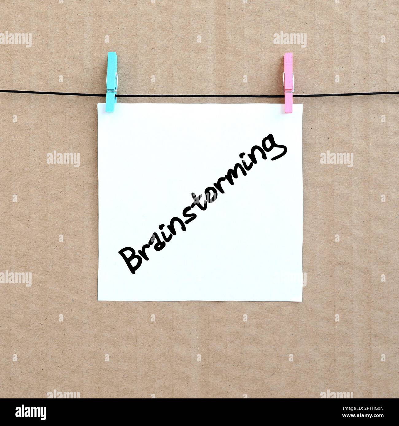 Brainstorming. Note is written on a white sticker that hangs with a ...