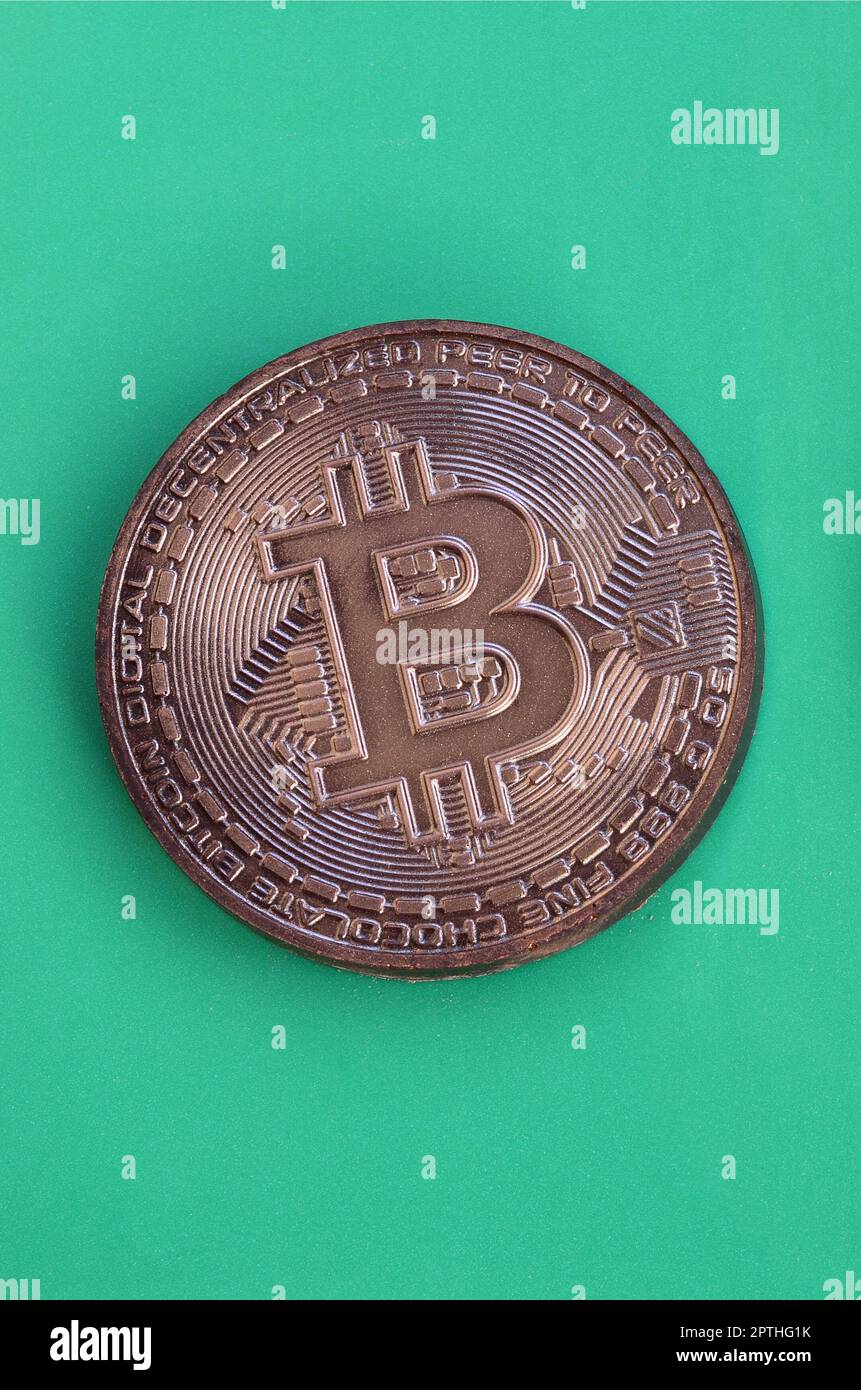 Chocolate product in the form of physical bitcoin lies on a green ...