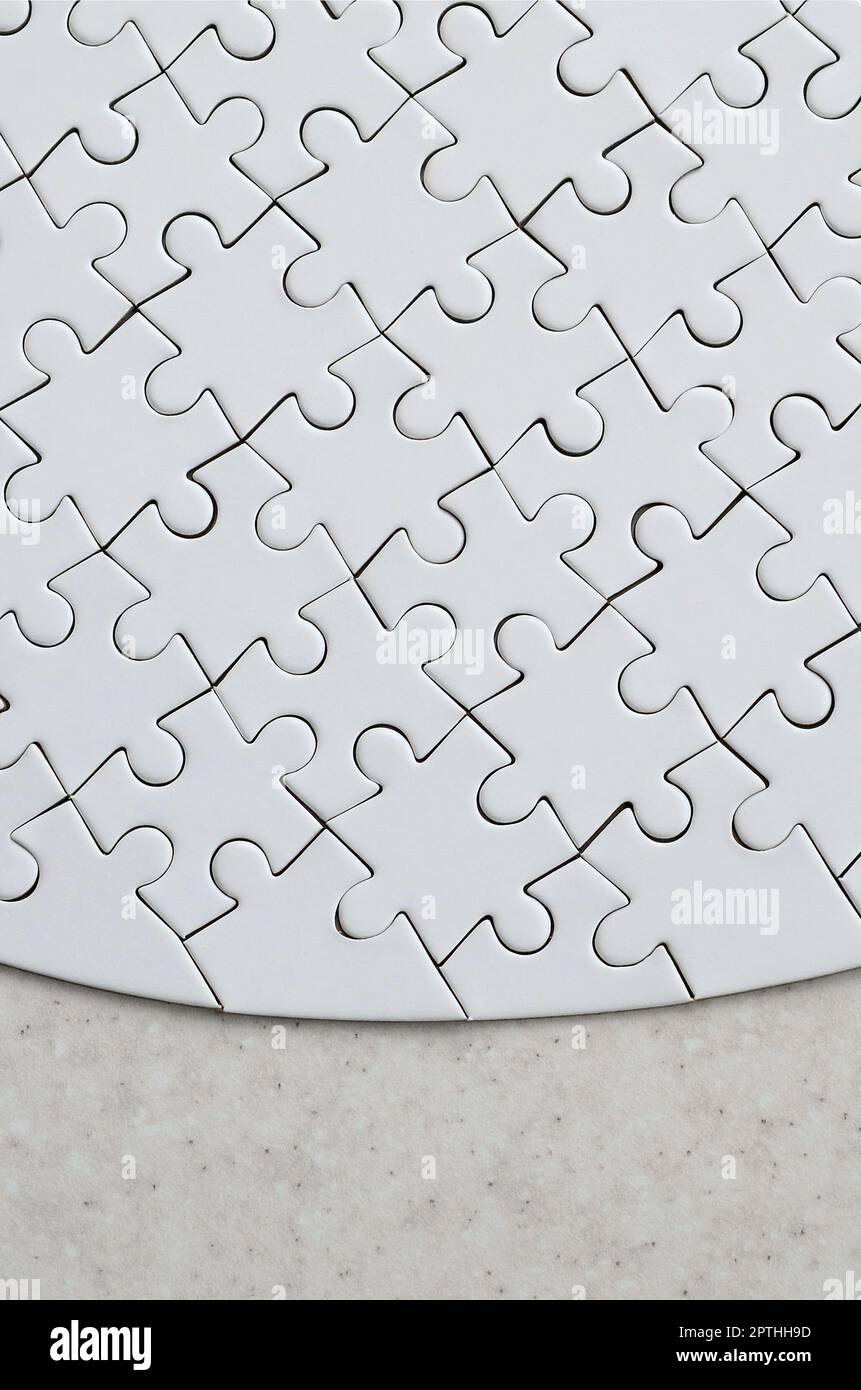 A white jigsaw puzzle in the complete form lies on a treated stone ...
