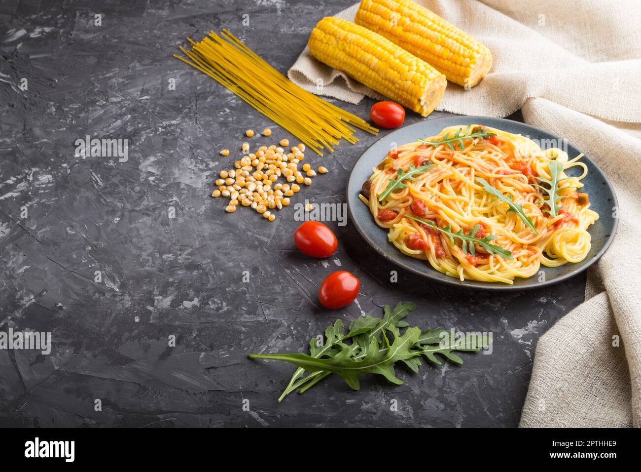 Corn noodles with tomato sauce and arugula on a black concrete ...