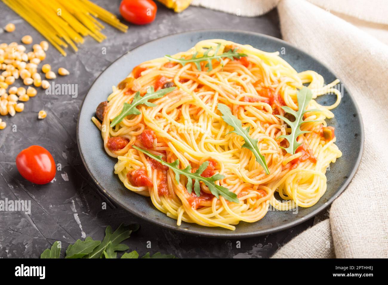 Corn noodles with tomato sauce and arugula on a black concrete ...