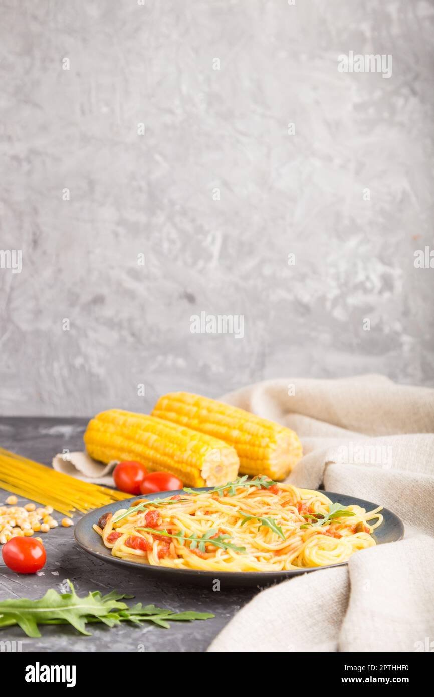 Corn noodles with tomato sauce and arugula on a black concrete ...