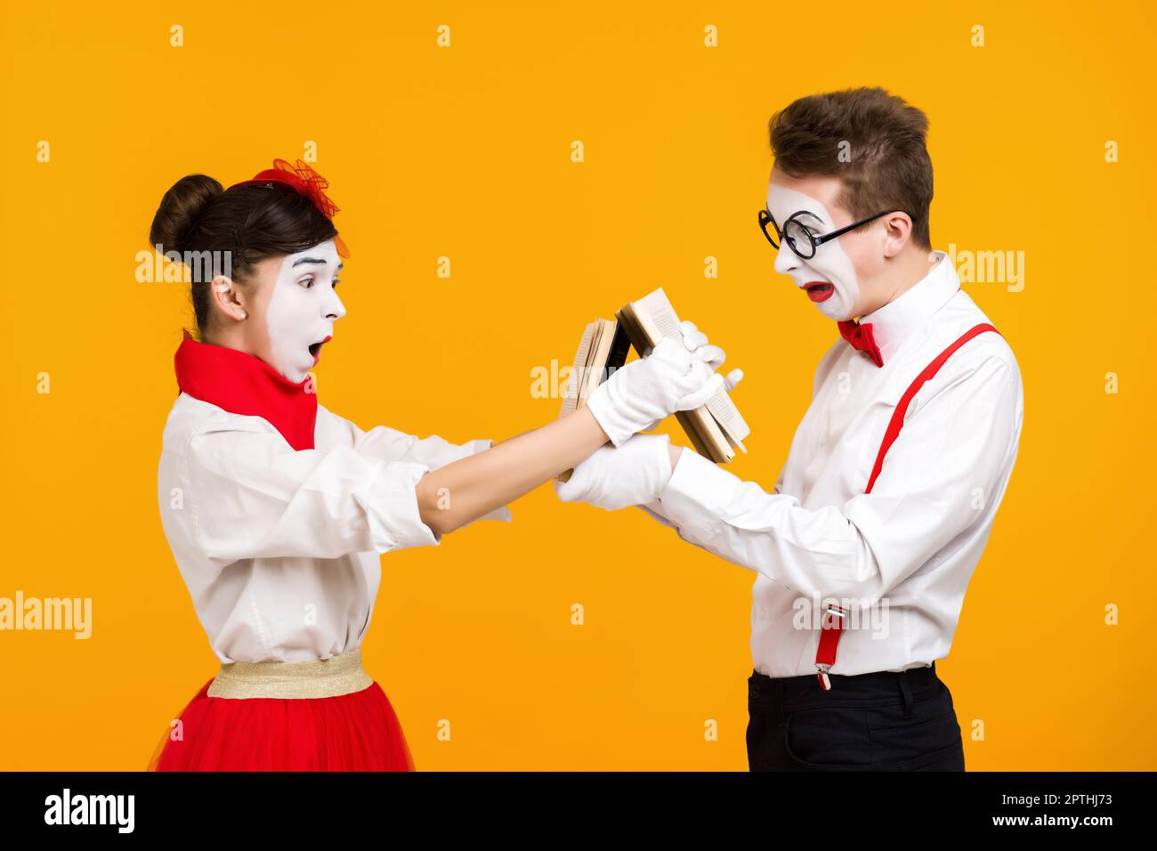 portrait of mime couple artist reading book isolated on yellow ...