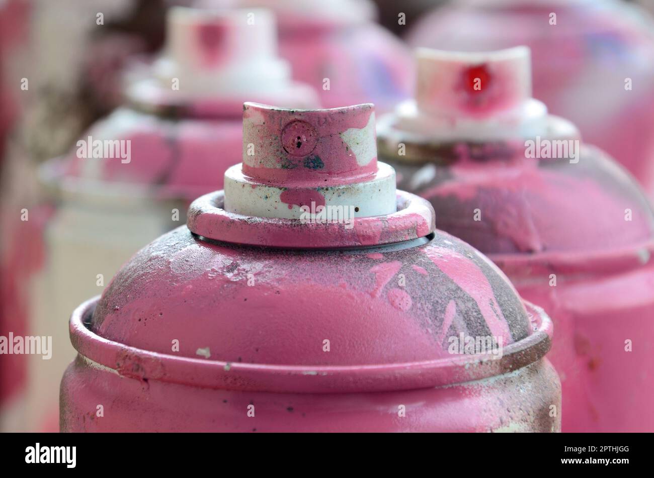 A lot of dirty and used aerosol cans of bright pink paint. Macro ...