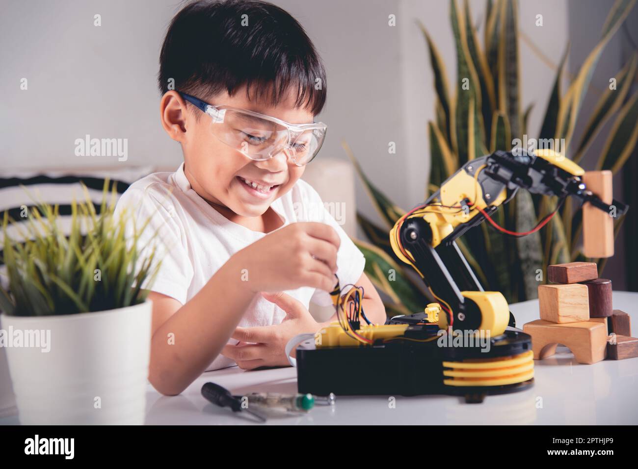 Happy Asian little kid boy using screwdriver to fixes screws robotic ...