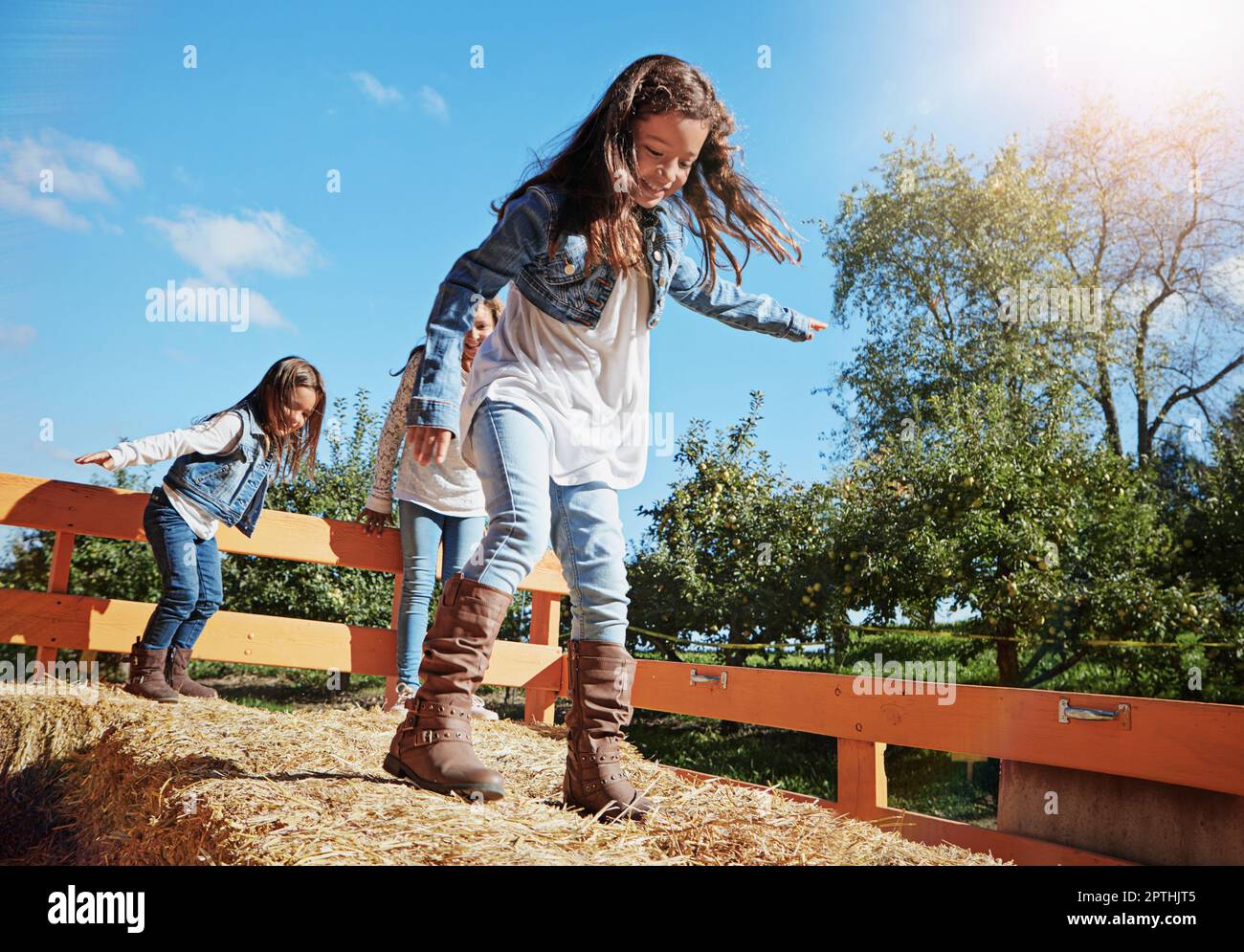 Kids at play on a bale of hay. three young sisters playing together on ...