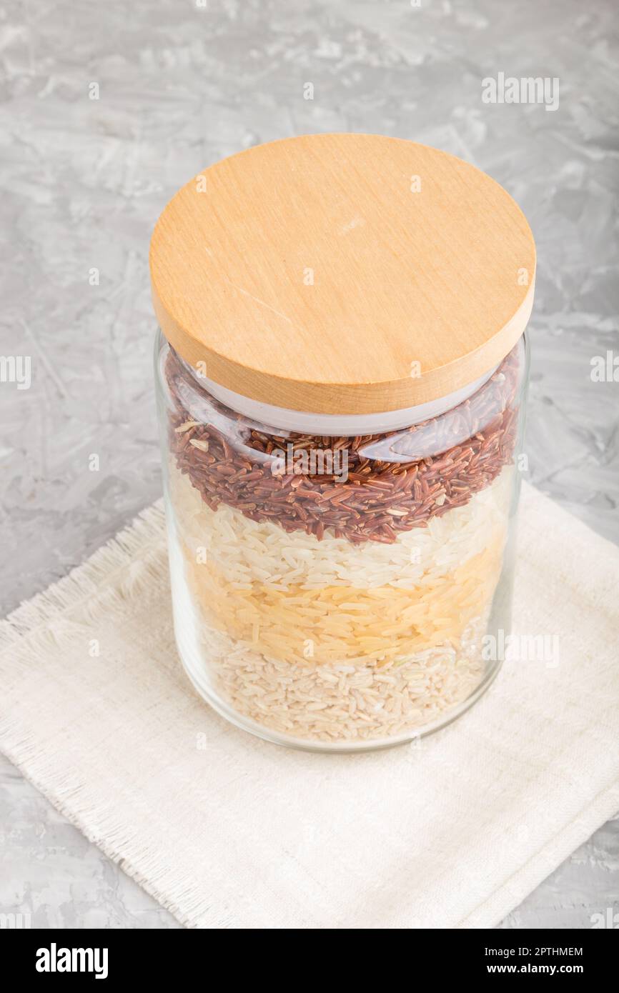 glass jar with different kinds of rice poured in layers on a gray ...