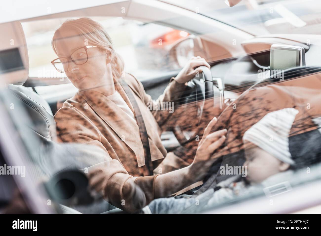 Mother reversing family car, looking for free parking space while ... Mother reversing family car, looking for free parking space while ...