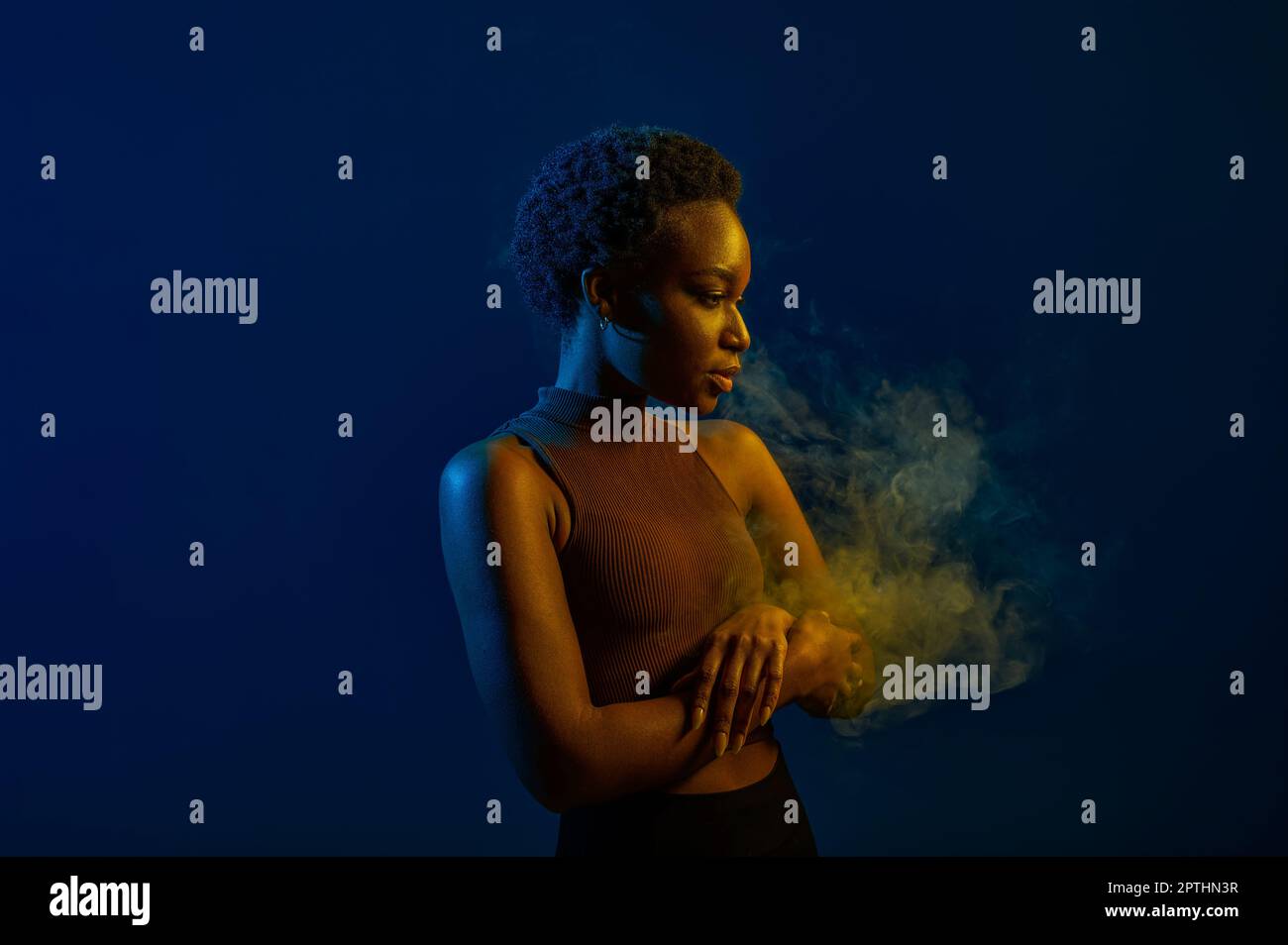 Portrait of woman blowing smoke curls from mouth over dark studio ...