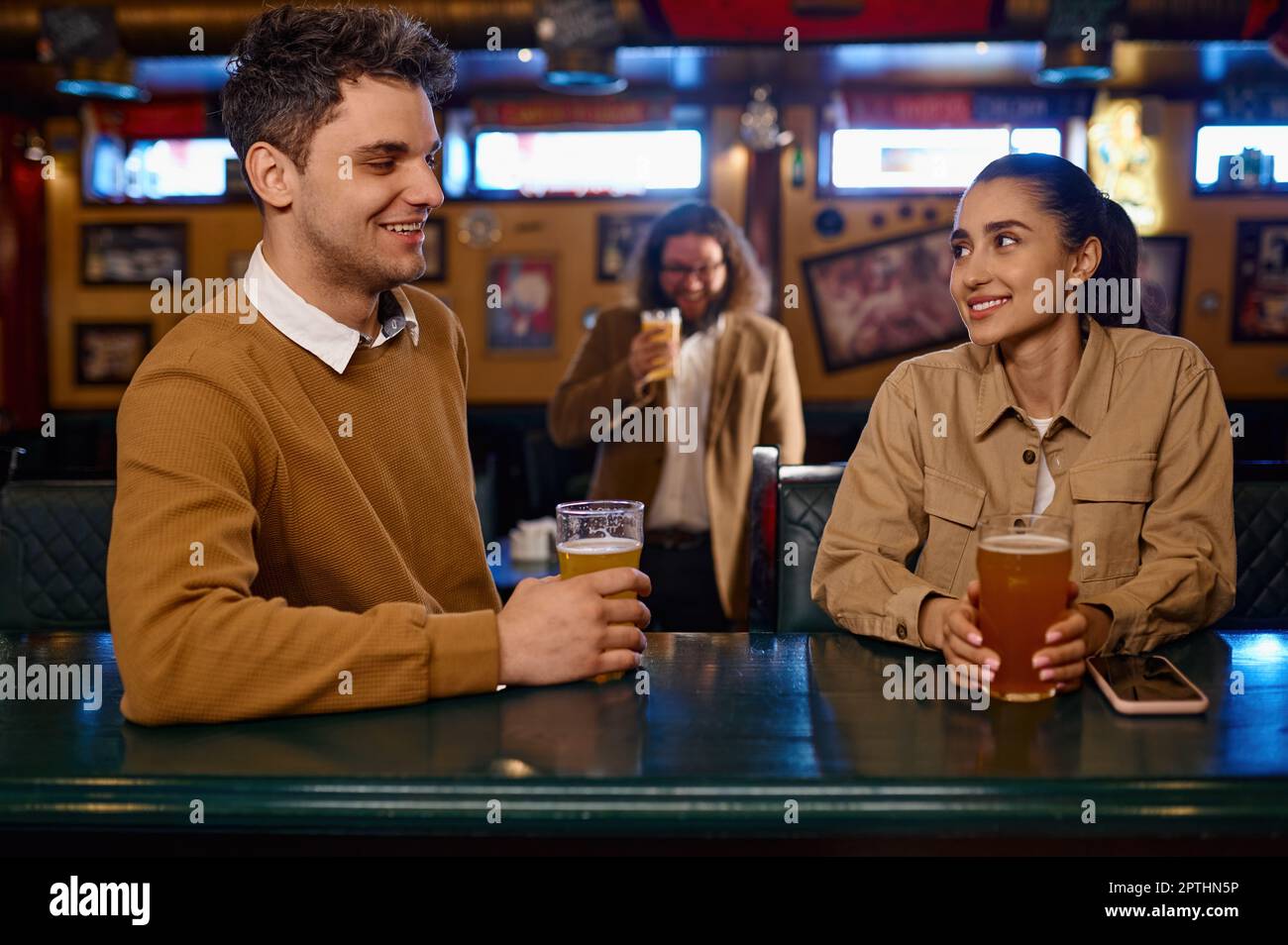 Young couple flirting and drinking beer sitting at sport bar counter ...