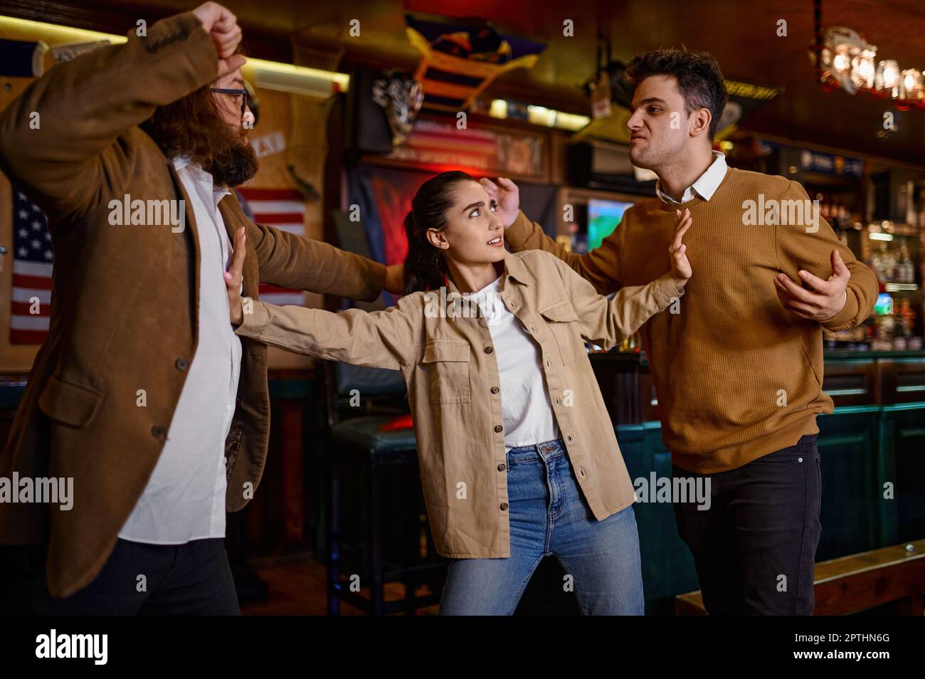 Woman trying to stop male friends fight at sport bar. Soccer fans ...
