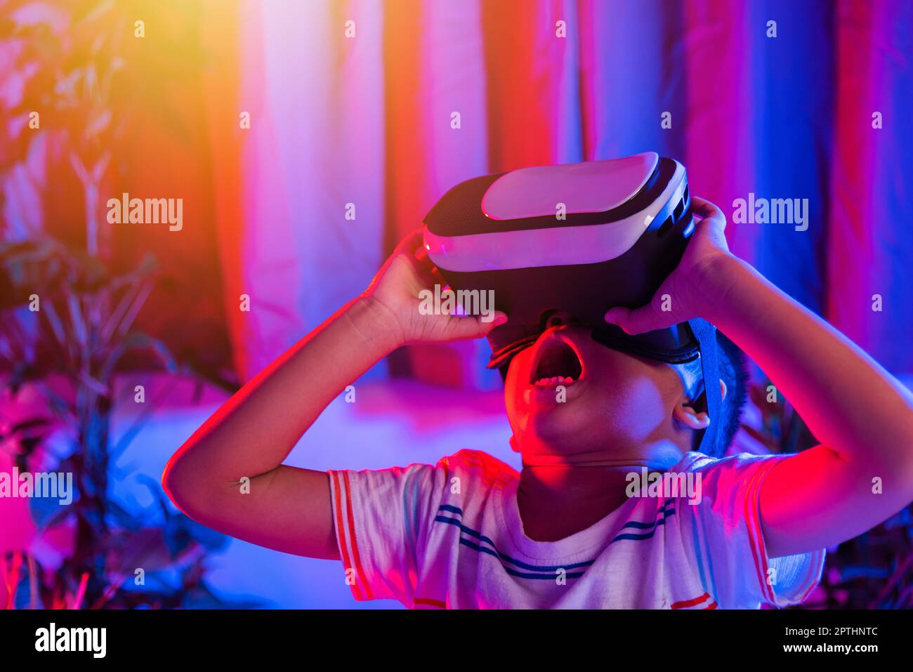 Asian little kid boy wearing virtual reality goggles experiencing ...