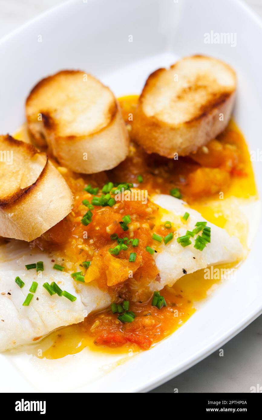 white fish with tomato sauce and roasted baguette slices Stock Photo ...