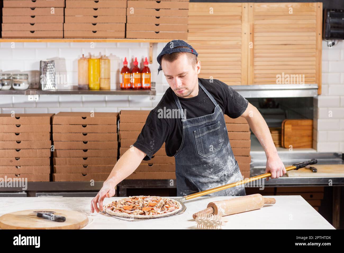 The chef prepares pizza. Raw pizza ready to bake. Cook in a blue apron ...