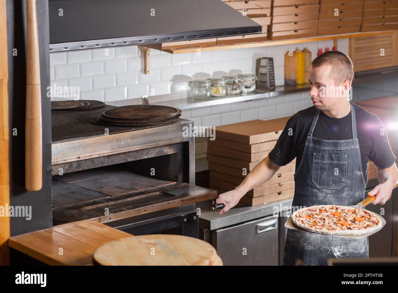 The chef prepares pizza. Raw pizza ready to bake. Cook in a blue apron ...