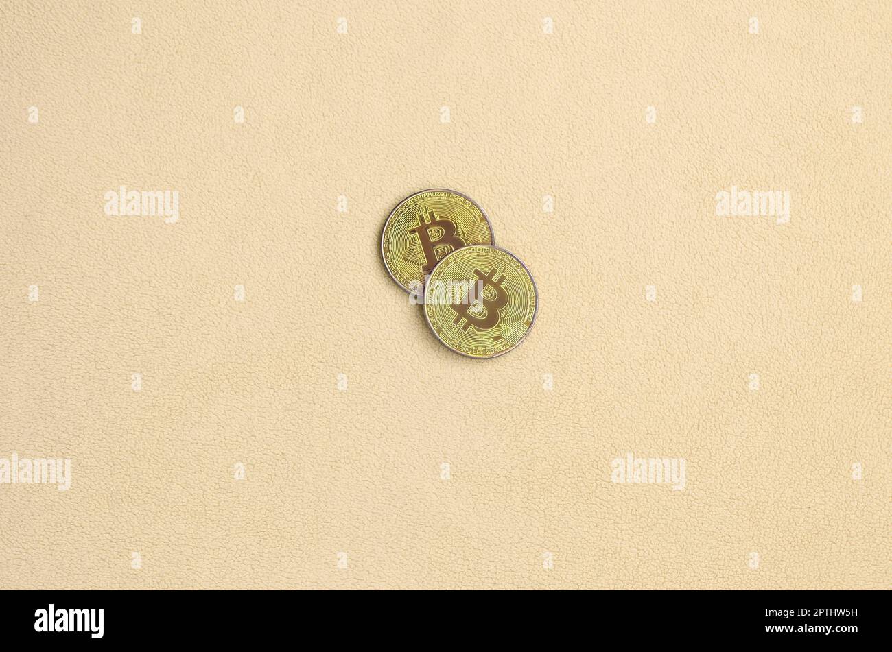 Two golden bitcoins lies on a blanket made of soft and fluffy light ...