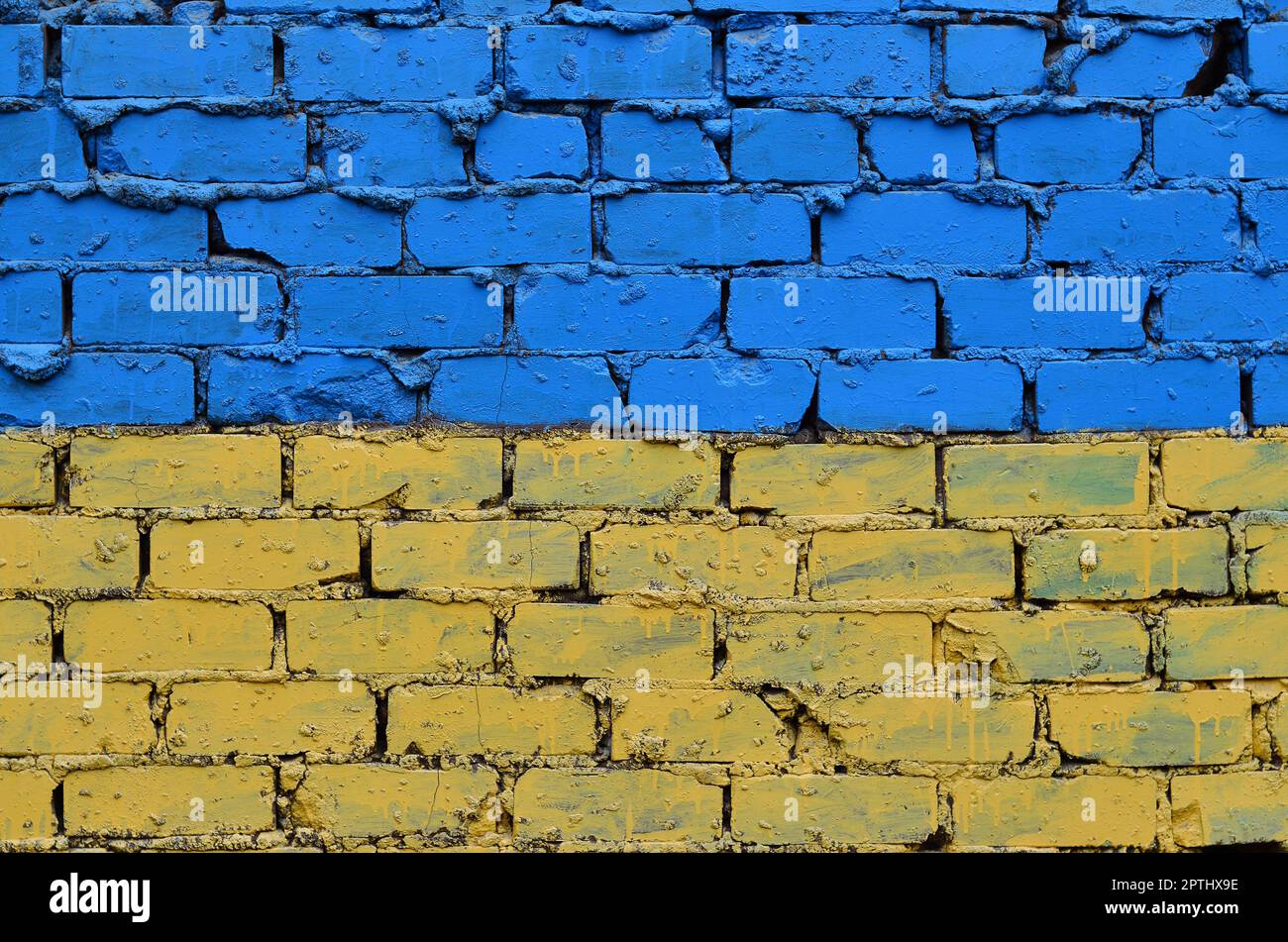 An old brick wall painted in the colors of the Ukrainian flag. Yellow ...