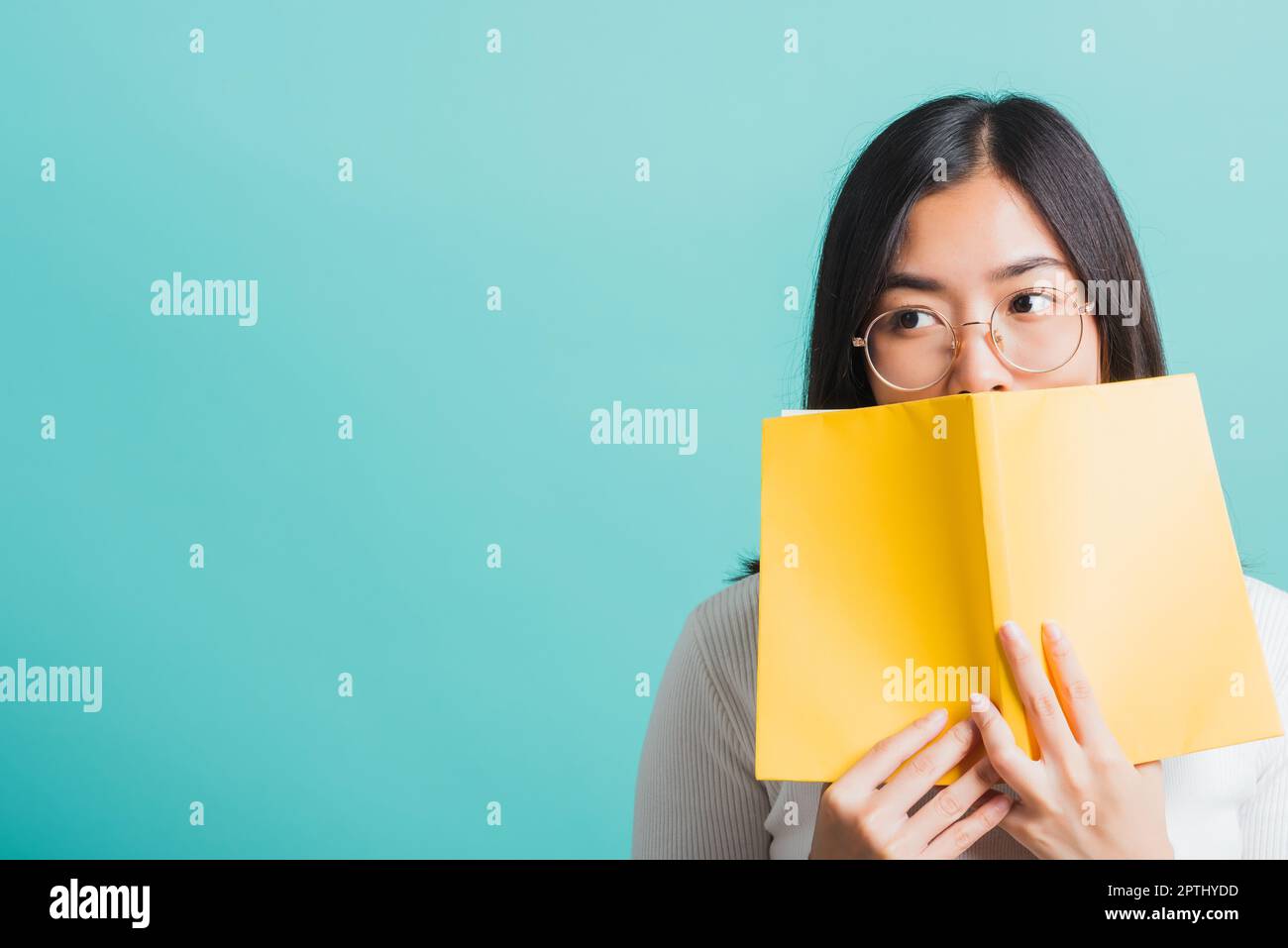 Young beautiful Asian woman hiding behind an open book, Portrait female ...