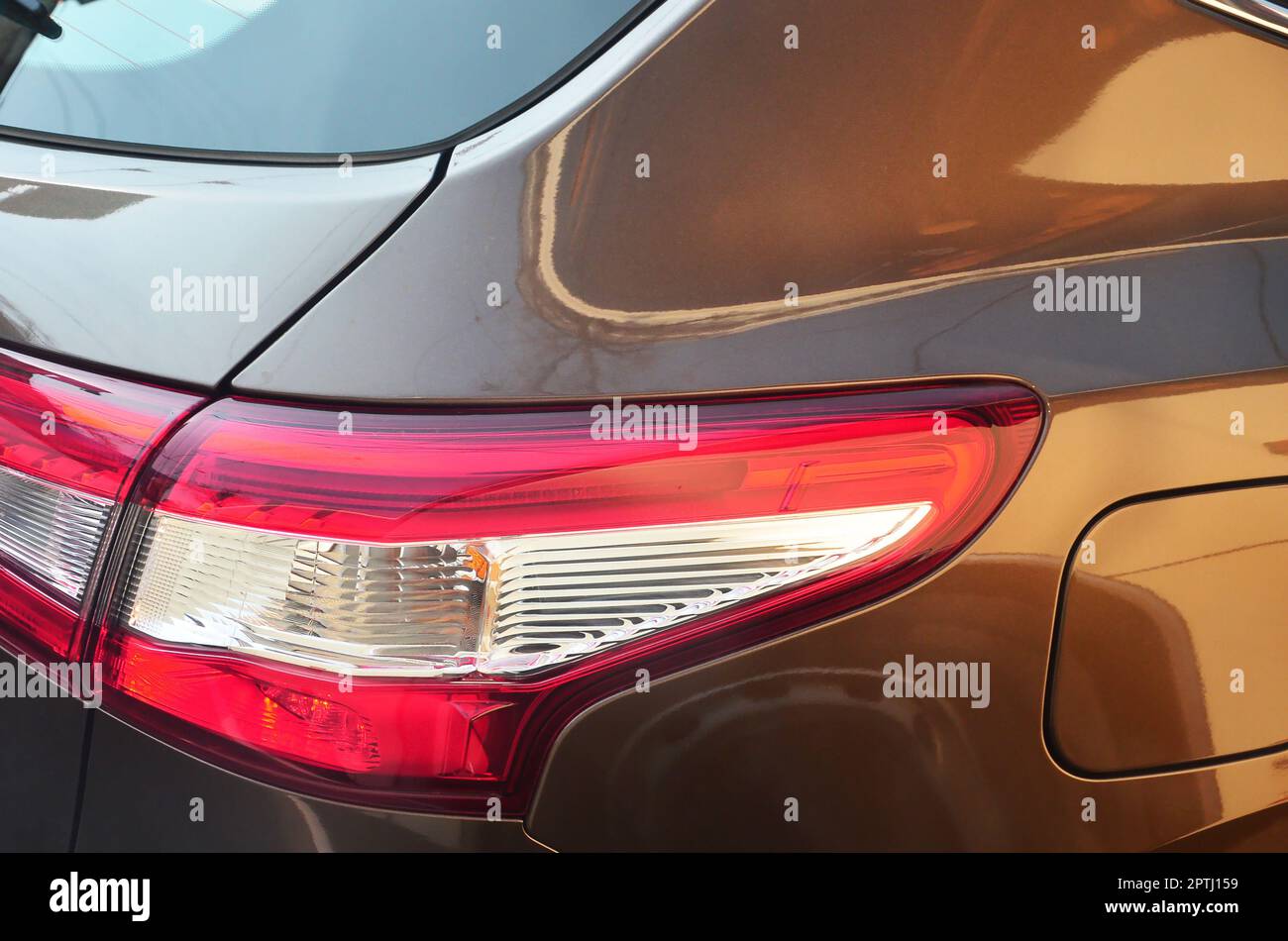 Red taillight of a brown passenger car close-up. Detailed photo of one ...