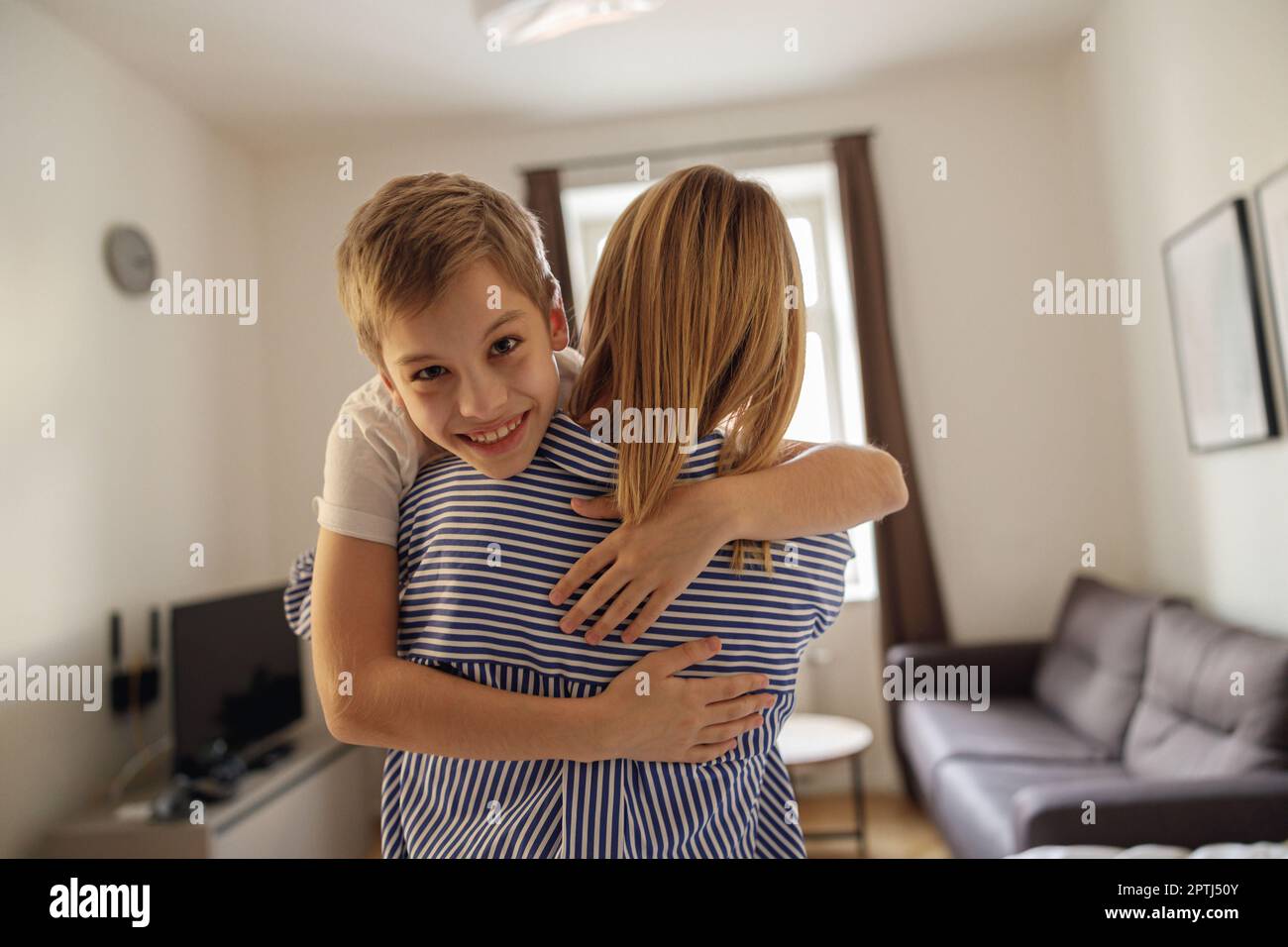 Back view of mom spends time with smiling son, holding him in her arms ...
