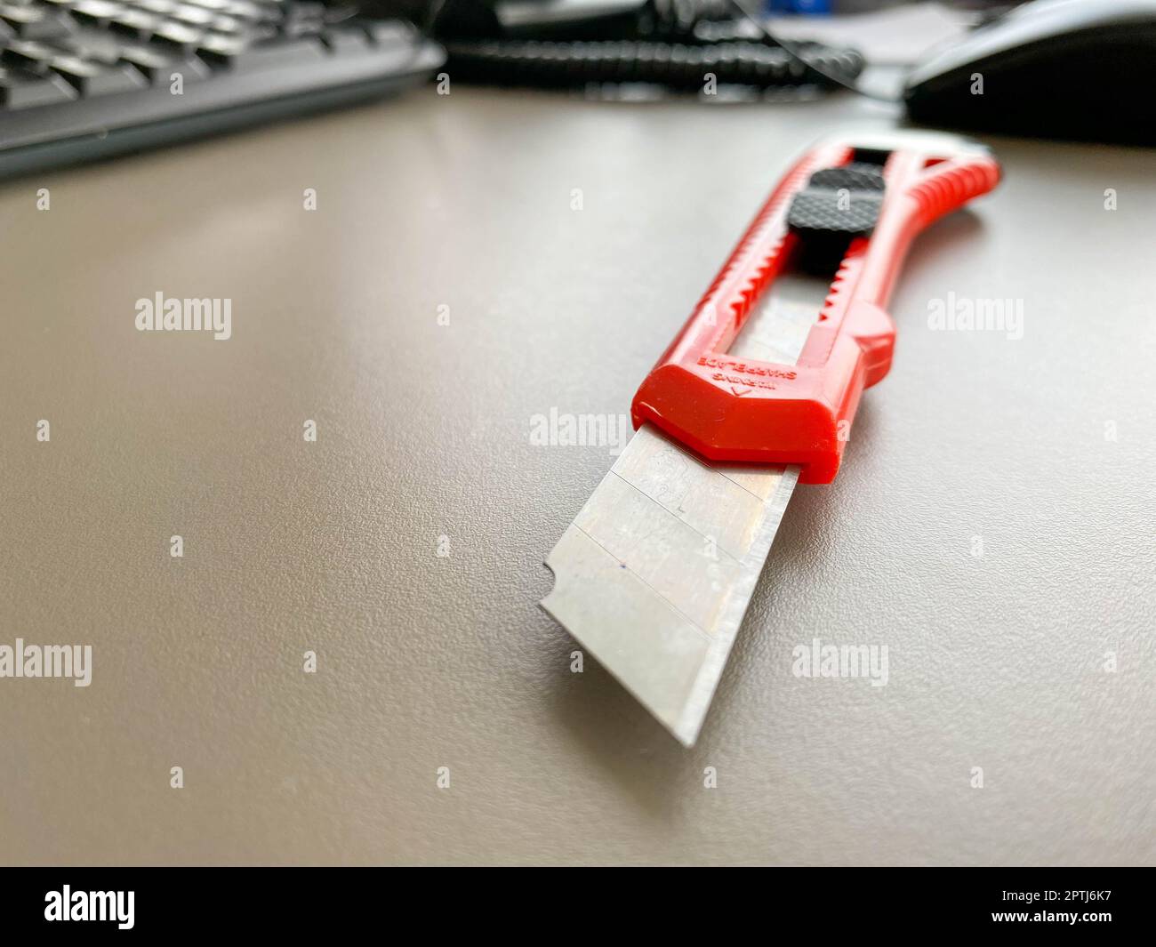 Red sharp office stationery knife with a paper cutting blade on a ...