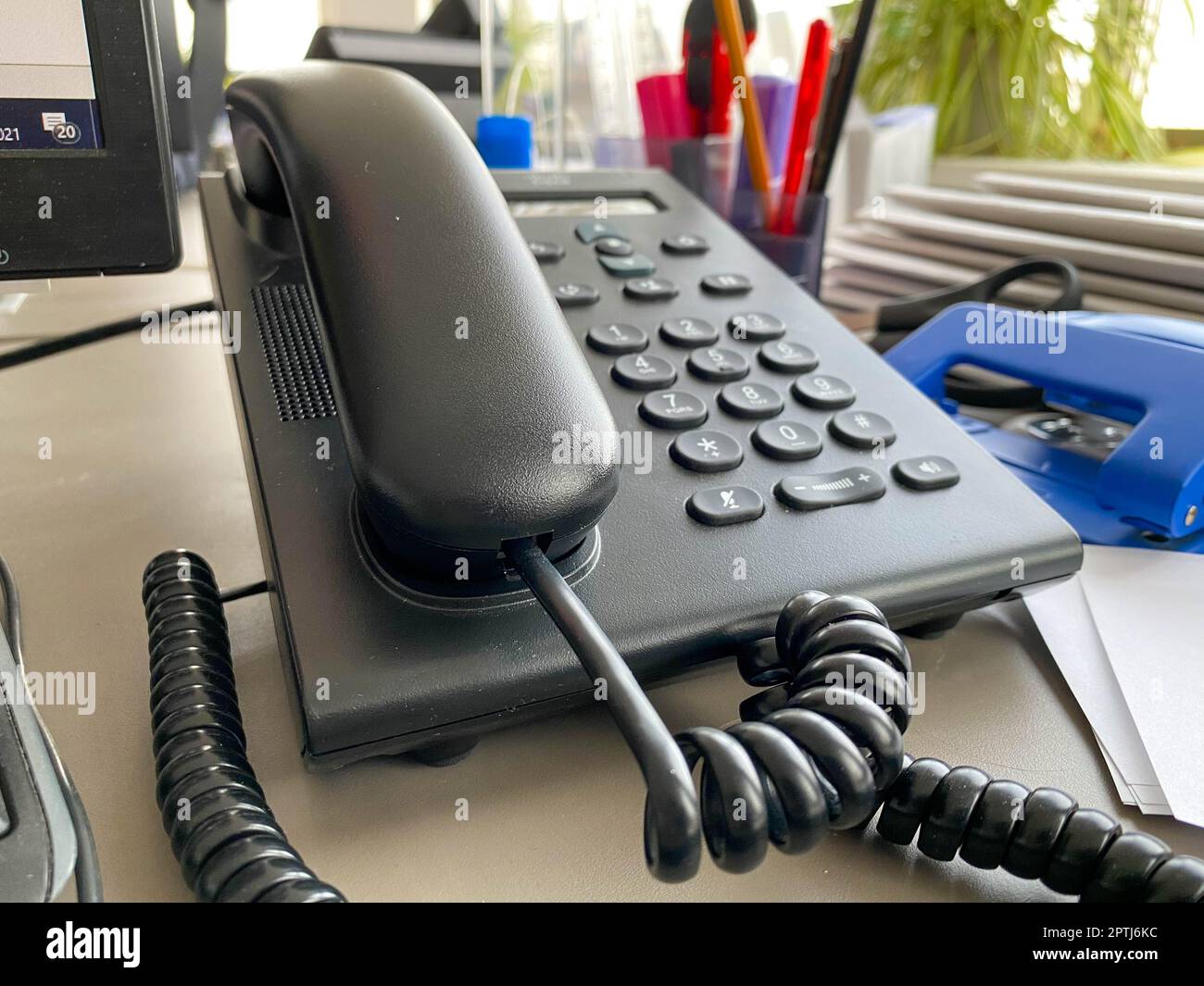 Black landline telephone with a tube, buttons and a wire on the work ...