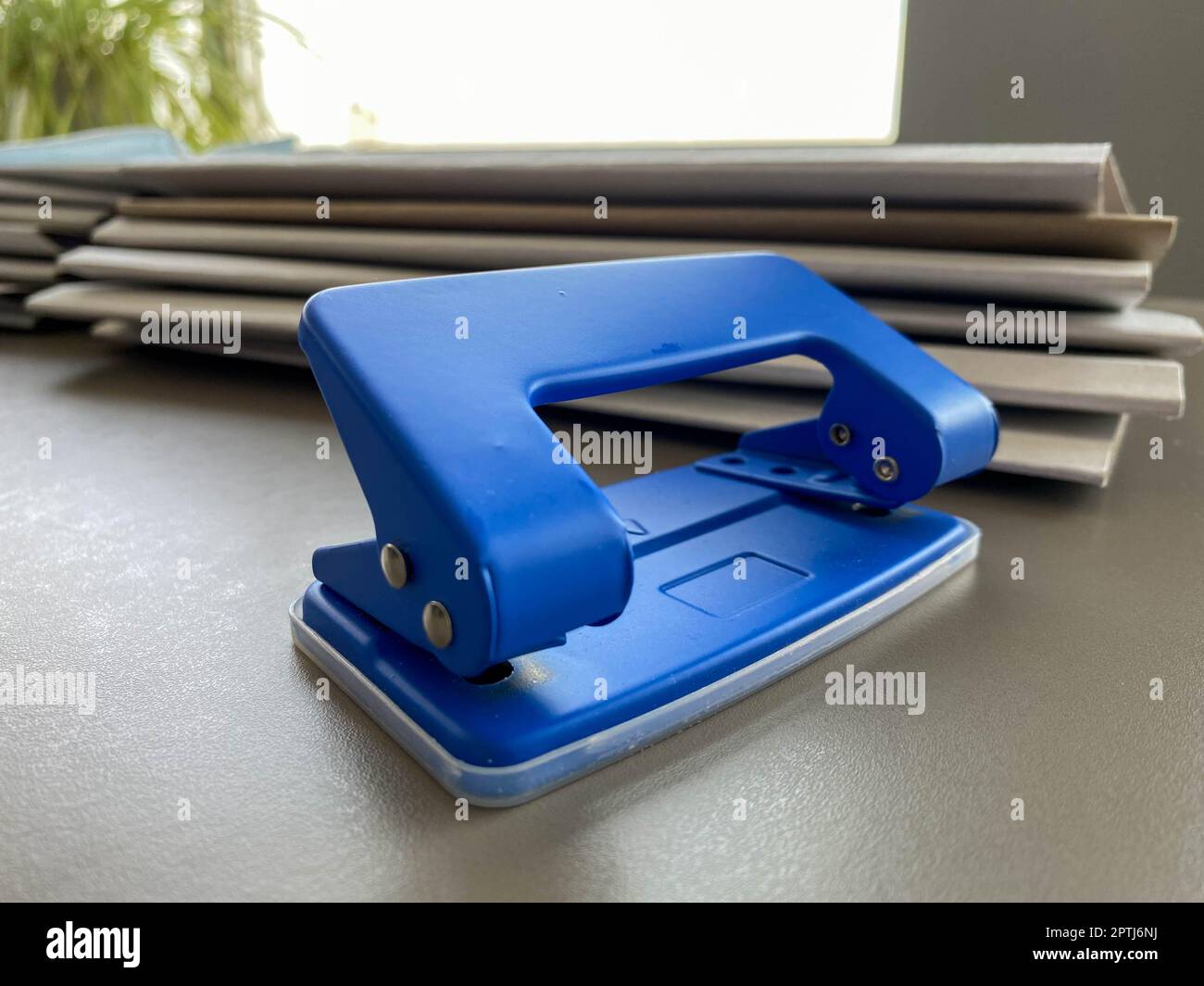 Blue iron metal office punch for punching holes in sheets of paper and ...