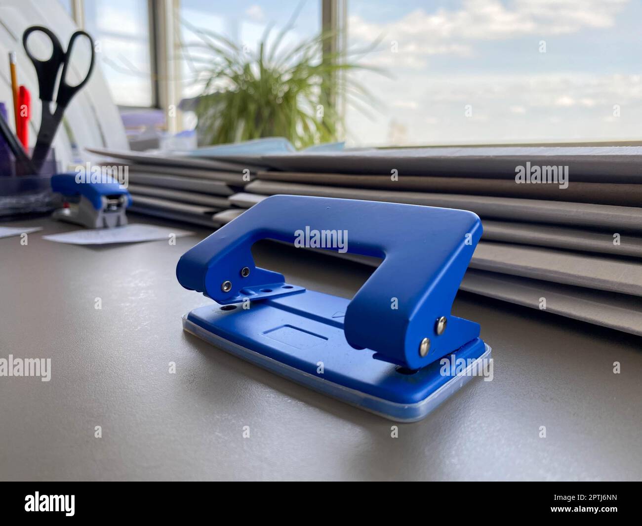 Blue iron metal office punch for punching holes in sheets of paper and ...