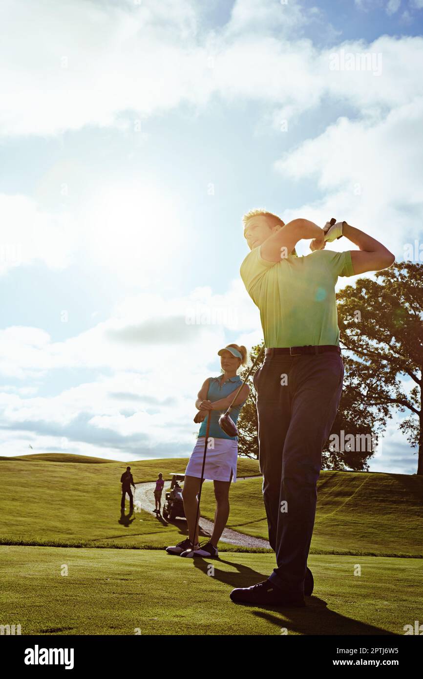 Flawless follow through. a couple playing golf together on a fairway ...