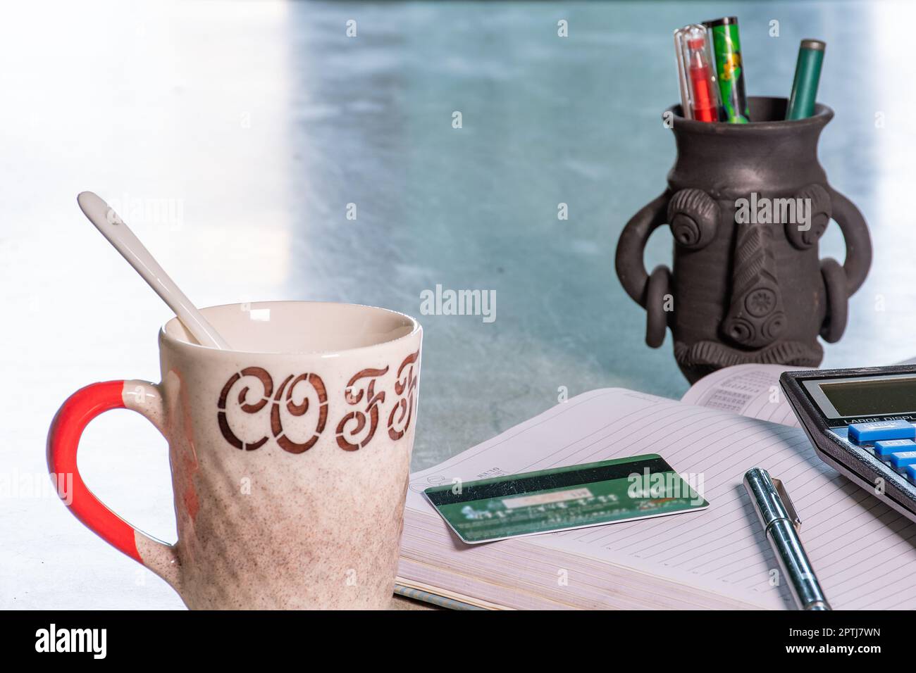 A coffee cup with a glass spoon and a diary, a debit card, a digital ...
