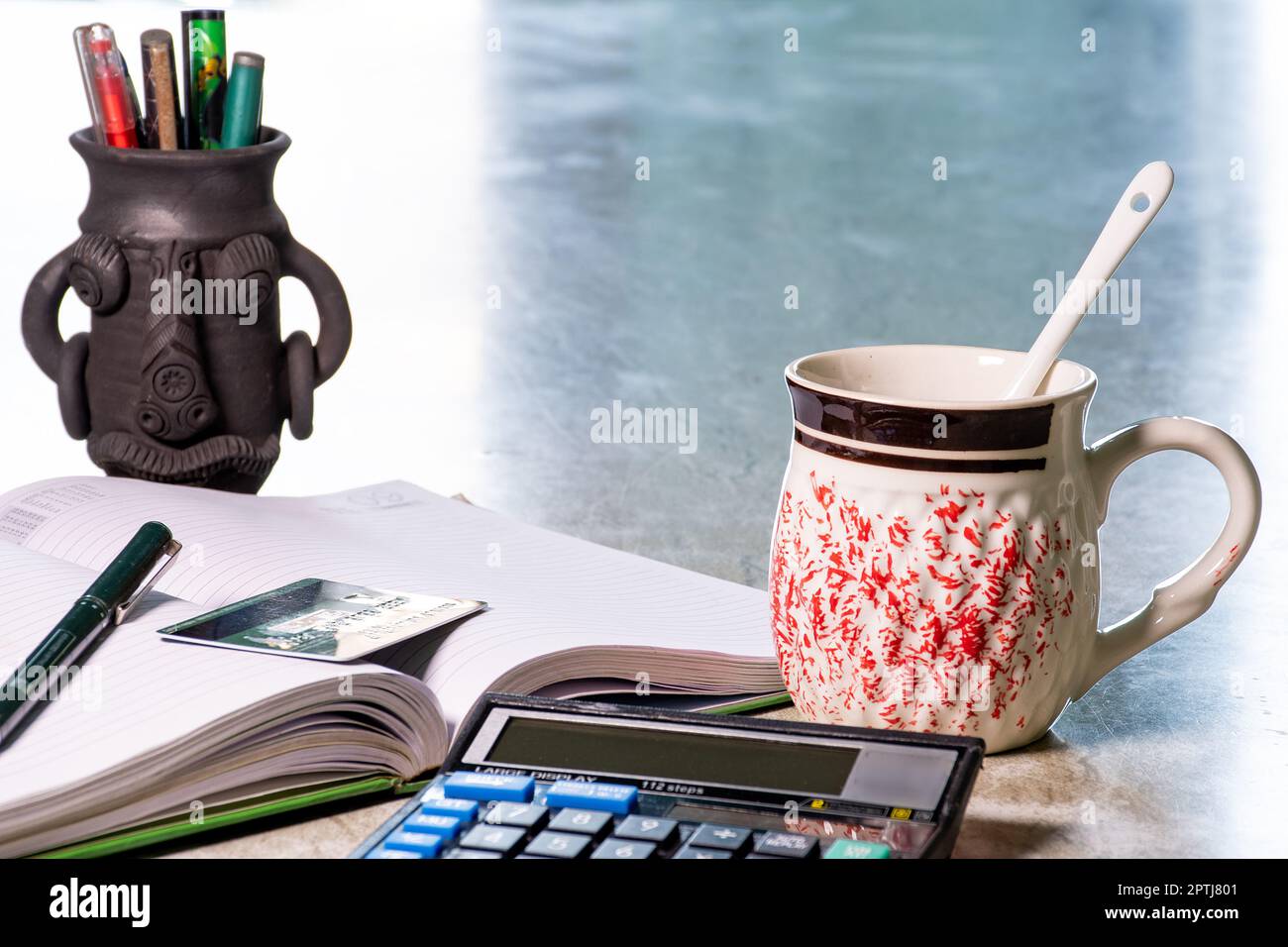 A coffee cup with a glass spoon and a diary, a debit card, a digital ...