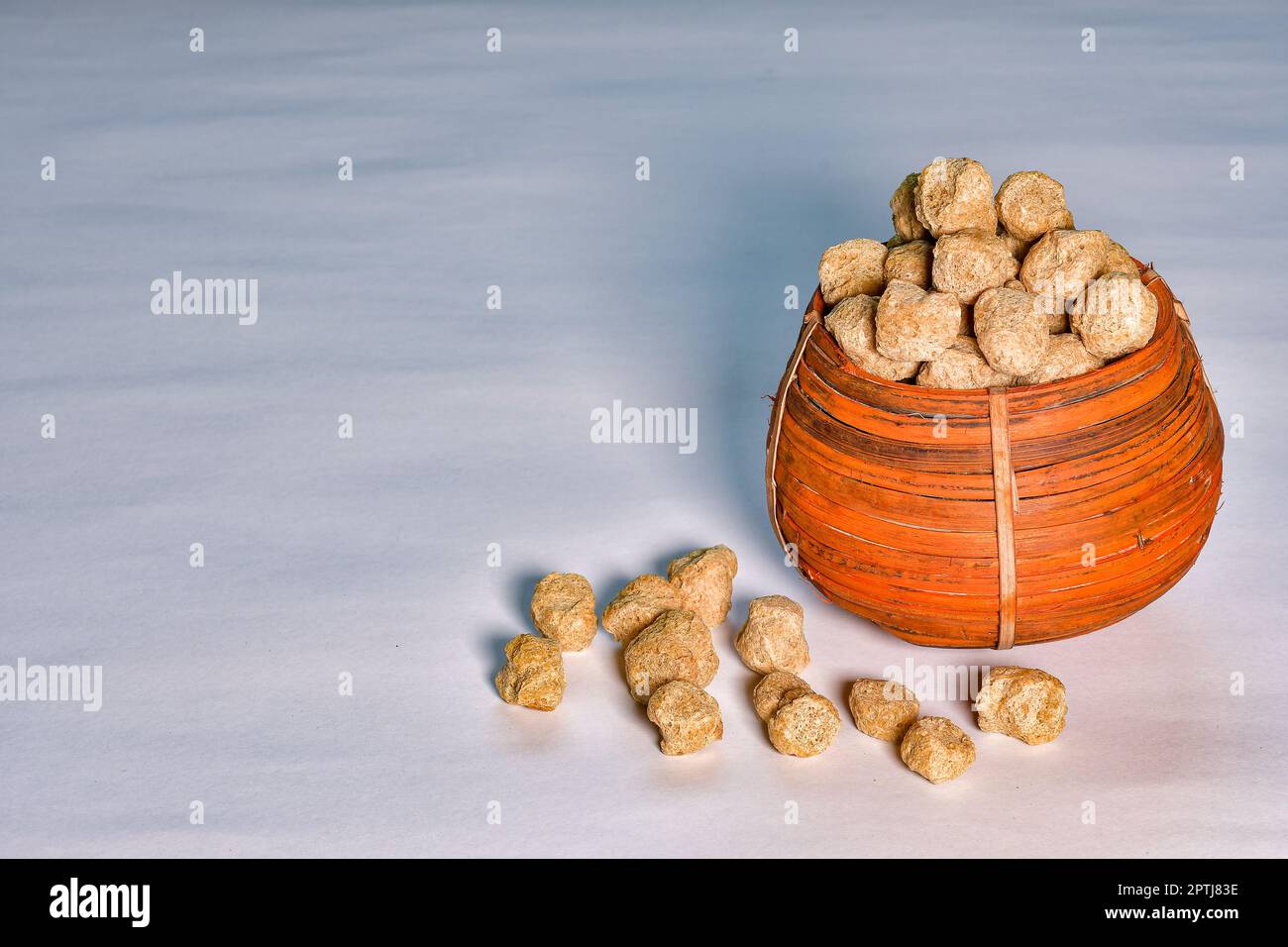 On a white background, there is a small cane bucket filled with soya ...