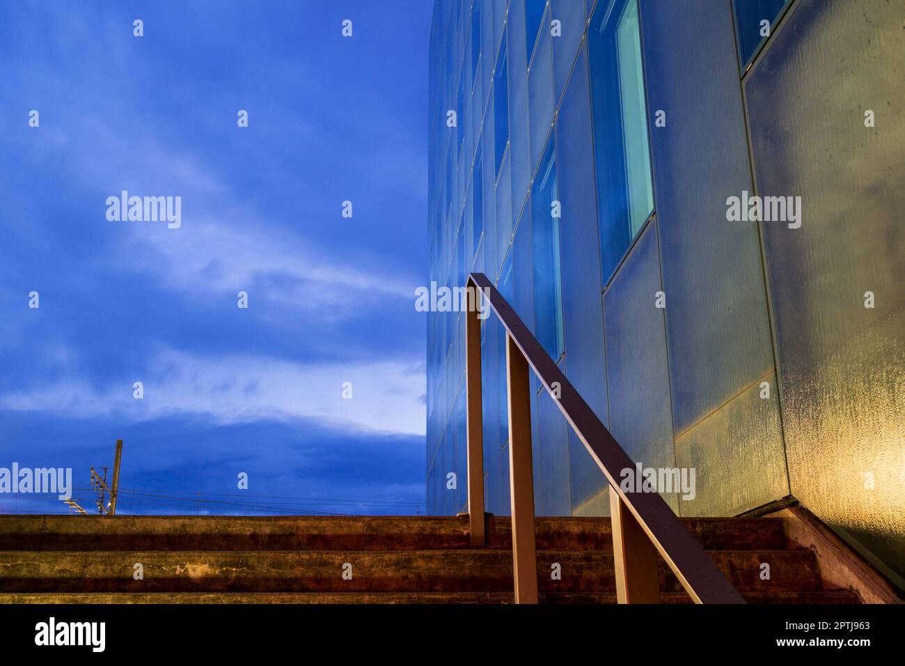Modern architecture in cold blue light of twilight hour and warm light ...