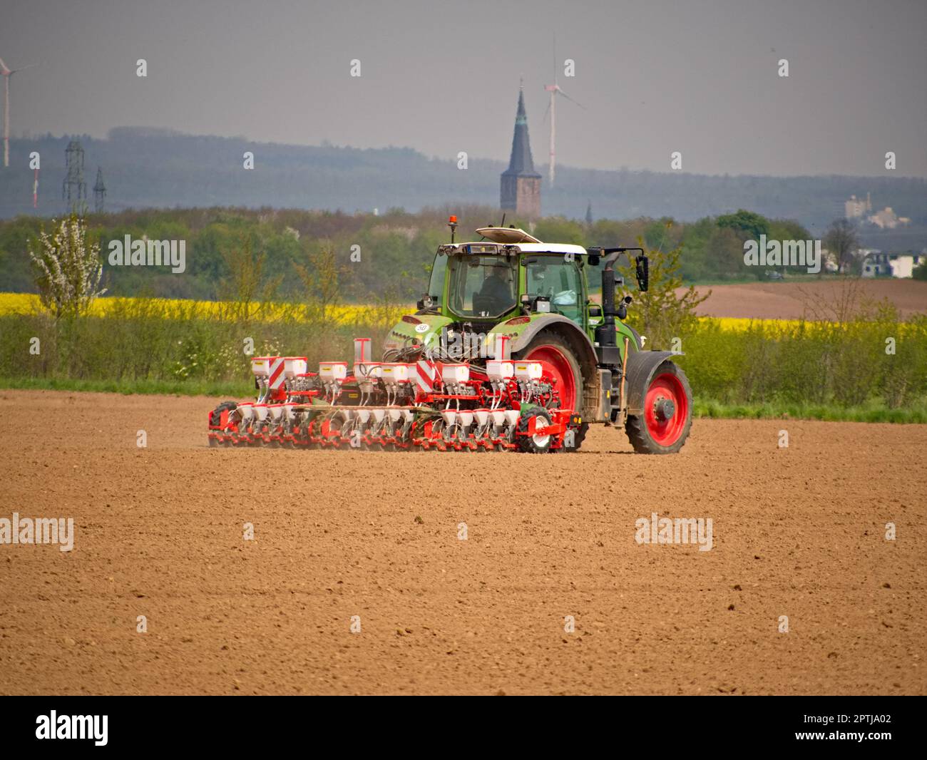 A tractor spreads fertilizer on a green field in Germany, symbolizing ...