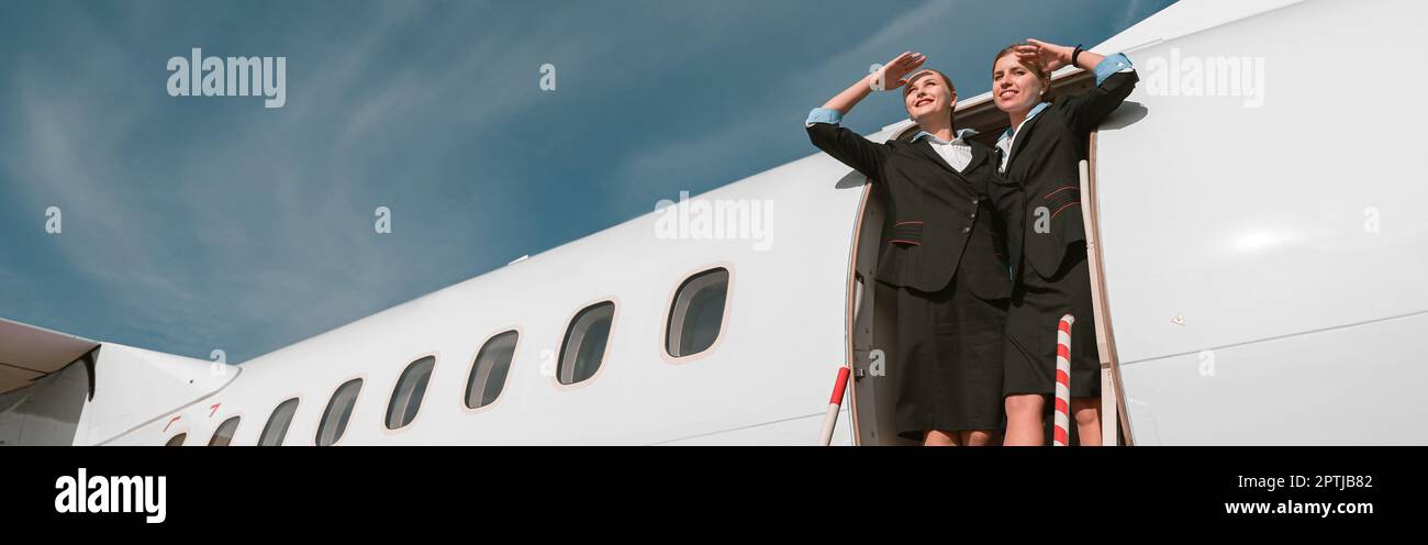 Two Women flight attendant standing on airplane stairs at airport and ...