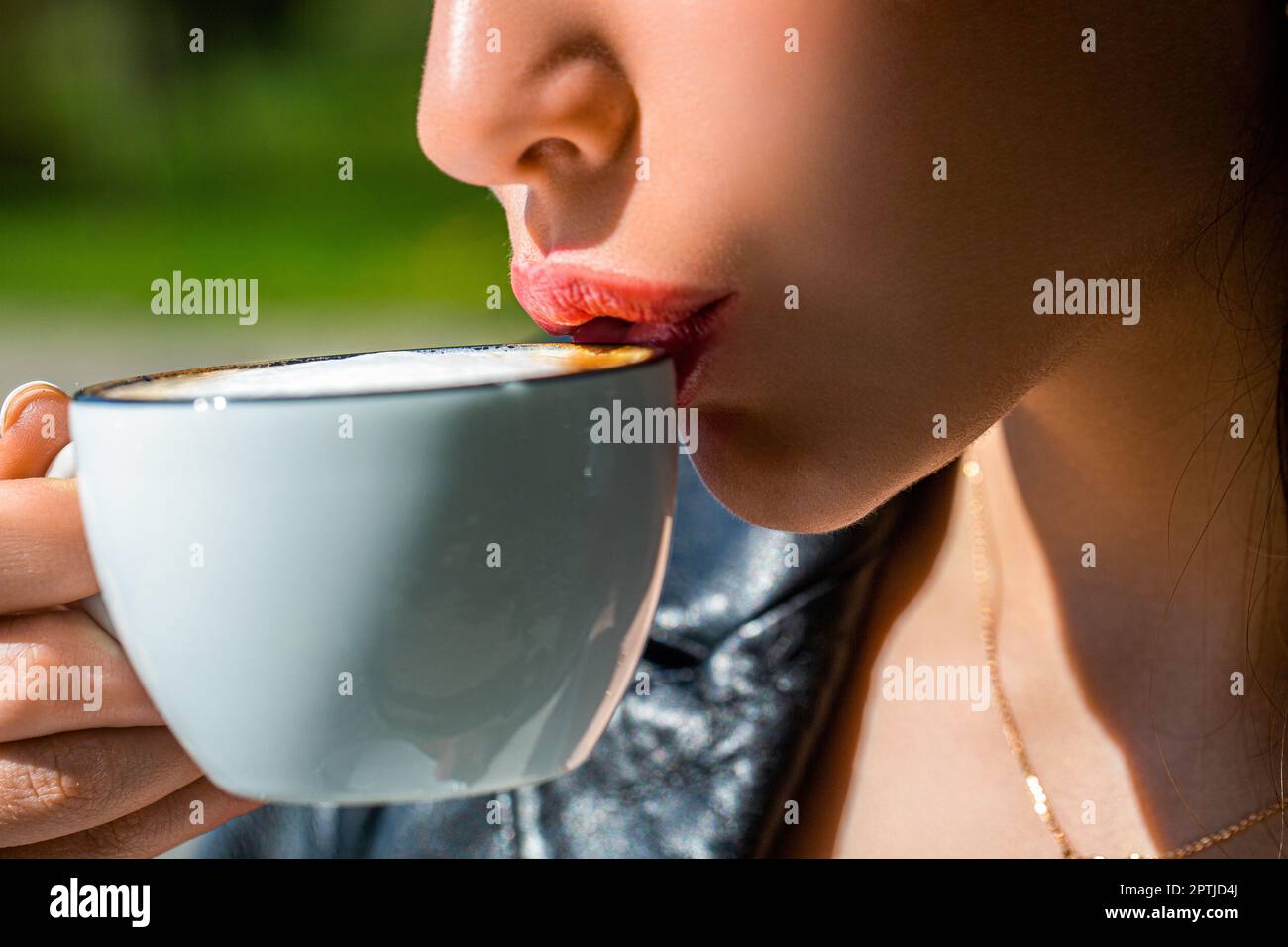 Closeup of the lips of a girl drinking coffee. White mug hot coffee in ...