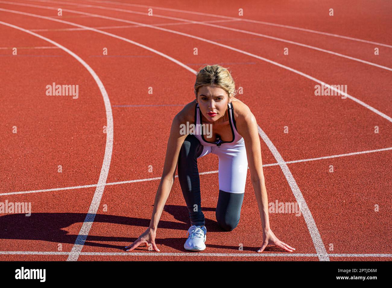Women sprinters at starting position ready for race on racetrack. Girl ... Women sprinters at starting position ready for race on racetrack. Girl ...