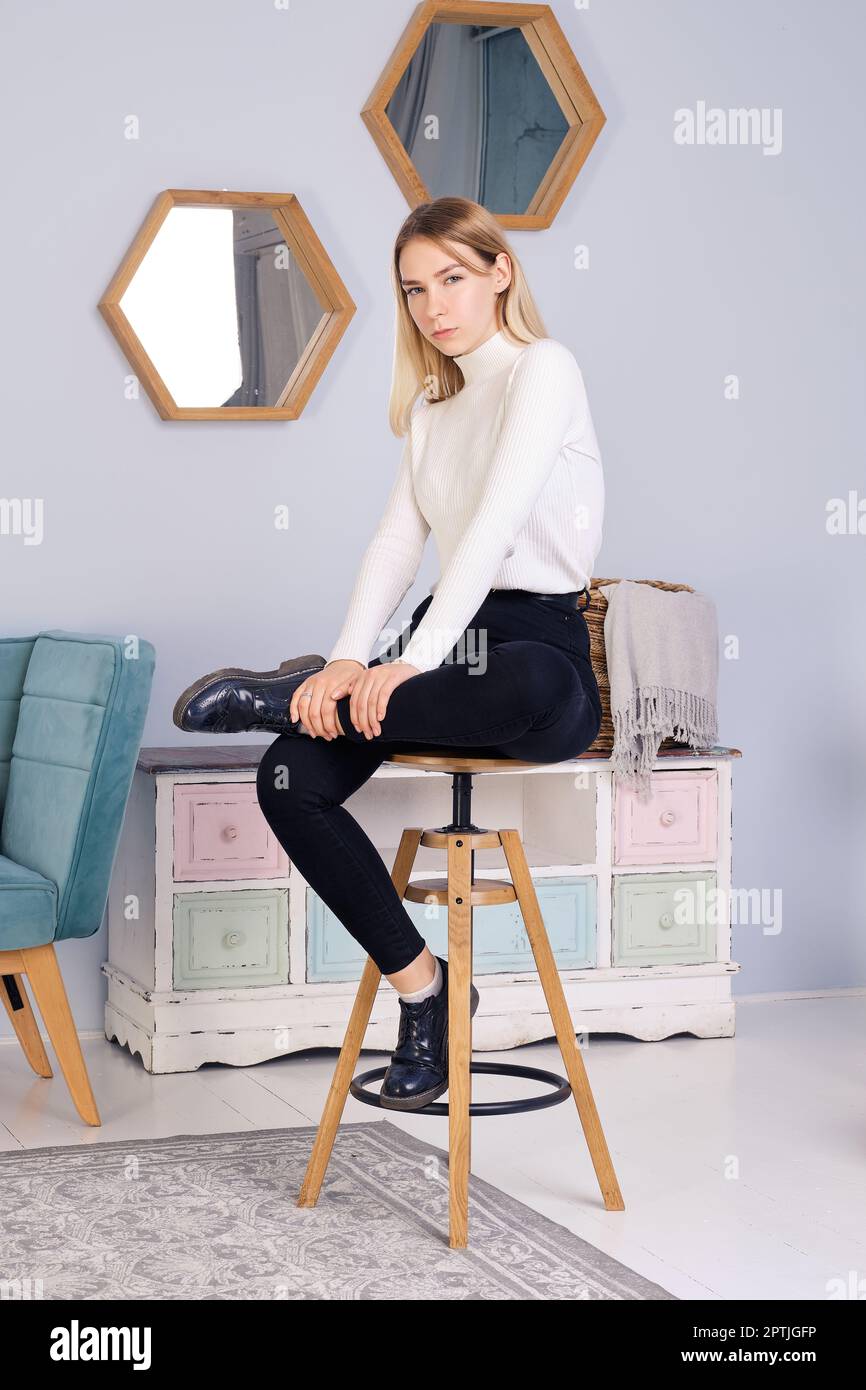 Full length portrait of young girl sitting on chair in livingroom Stock ...