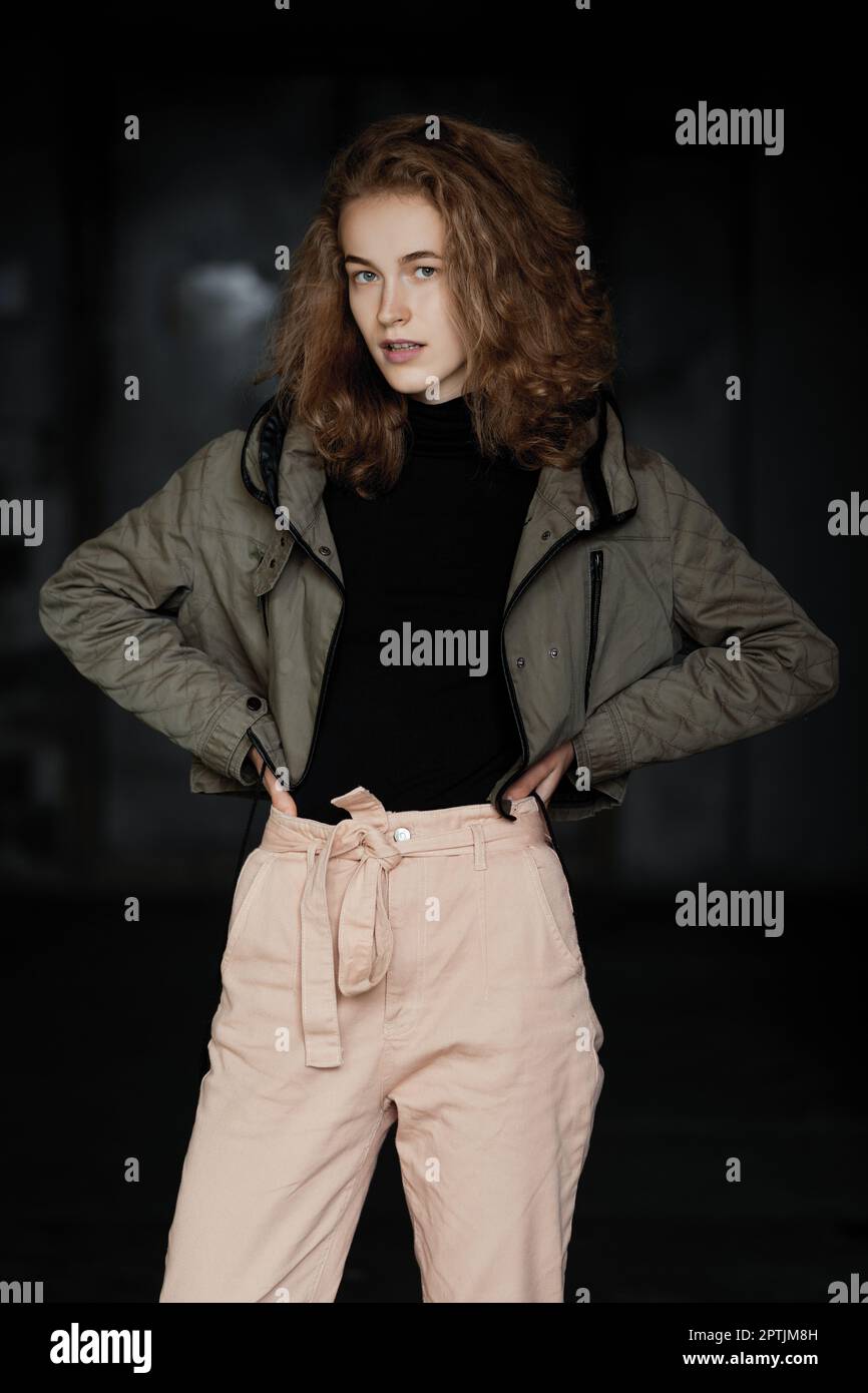 Low key portrait of a student girl in jacket, sweater and trousers ...