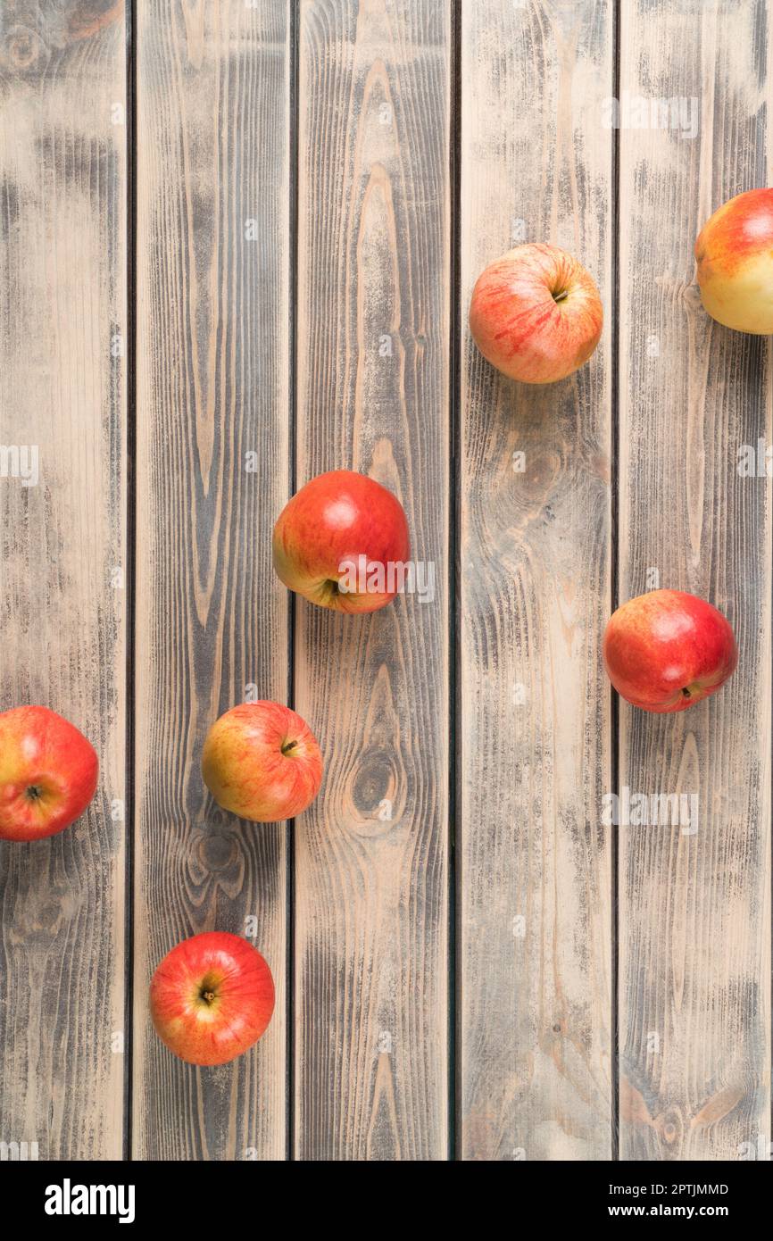 Vertical photo of scattered fresh red raw apples on wooden table ...