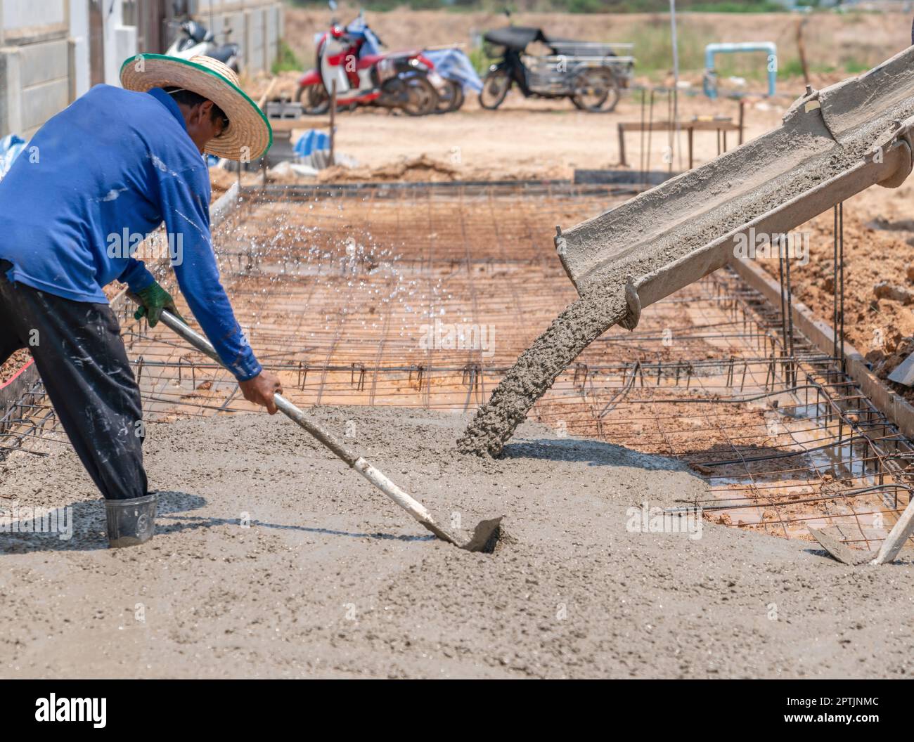 Worker spreading concrete with rakes at construction site Stock Photo ...